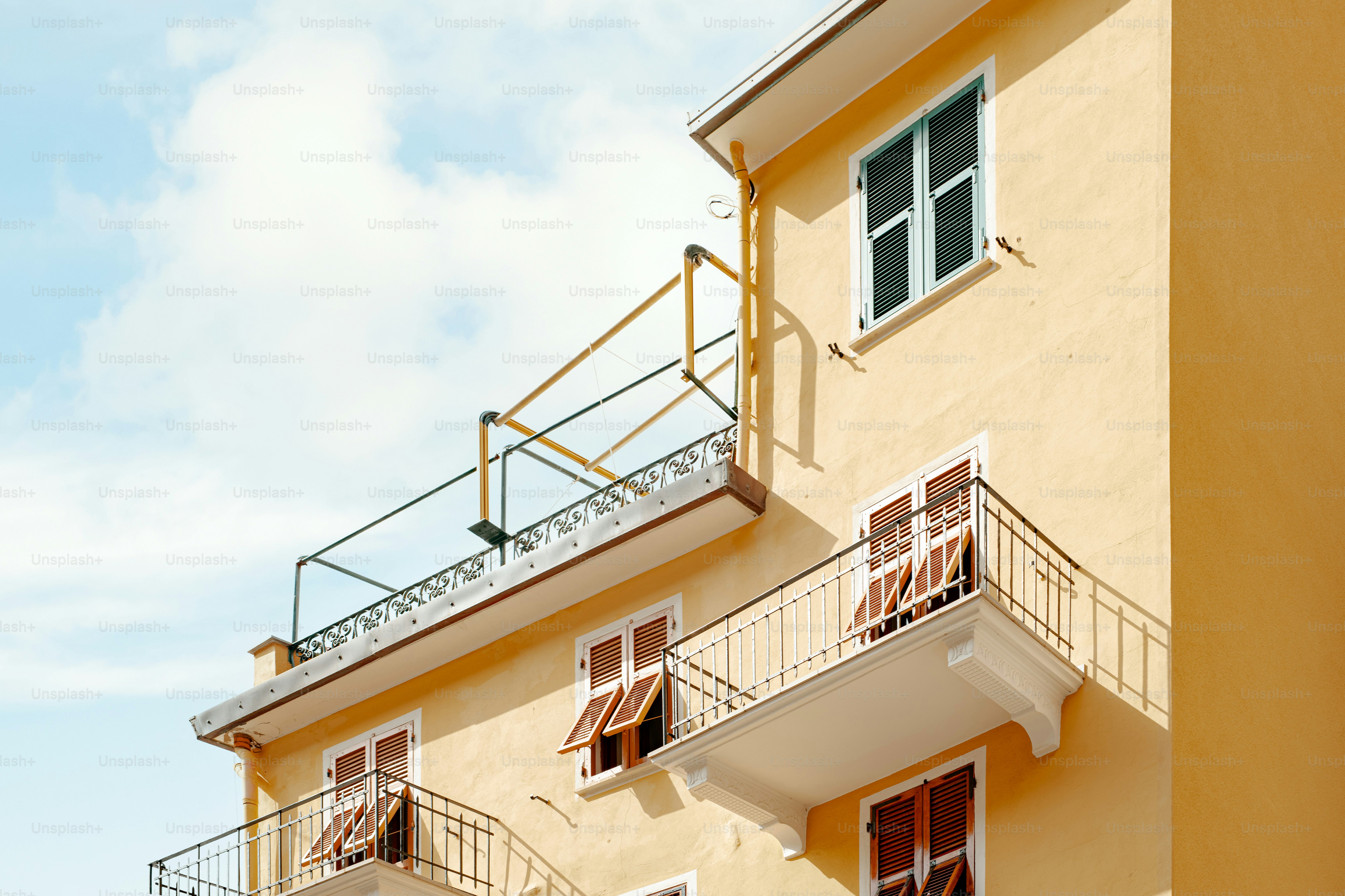 A tall yellow building with a balcony and balconies photo – Manarola ...
