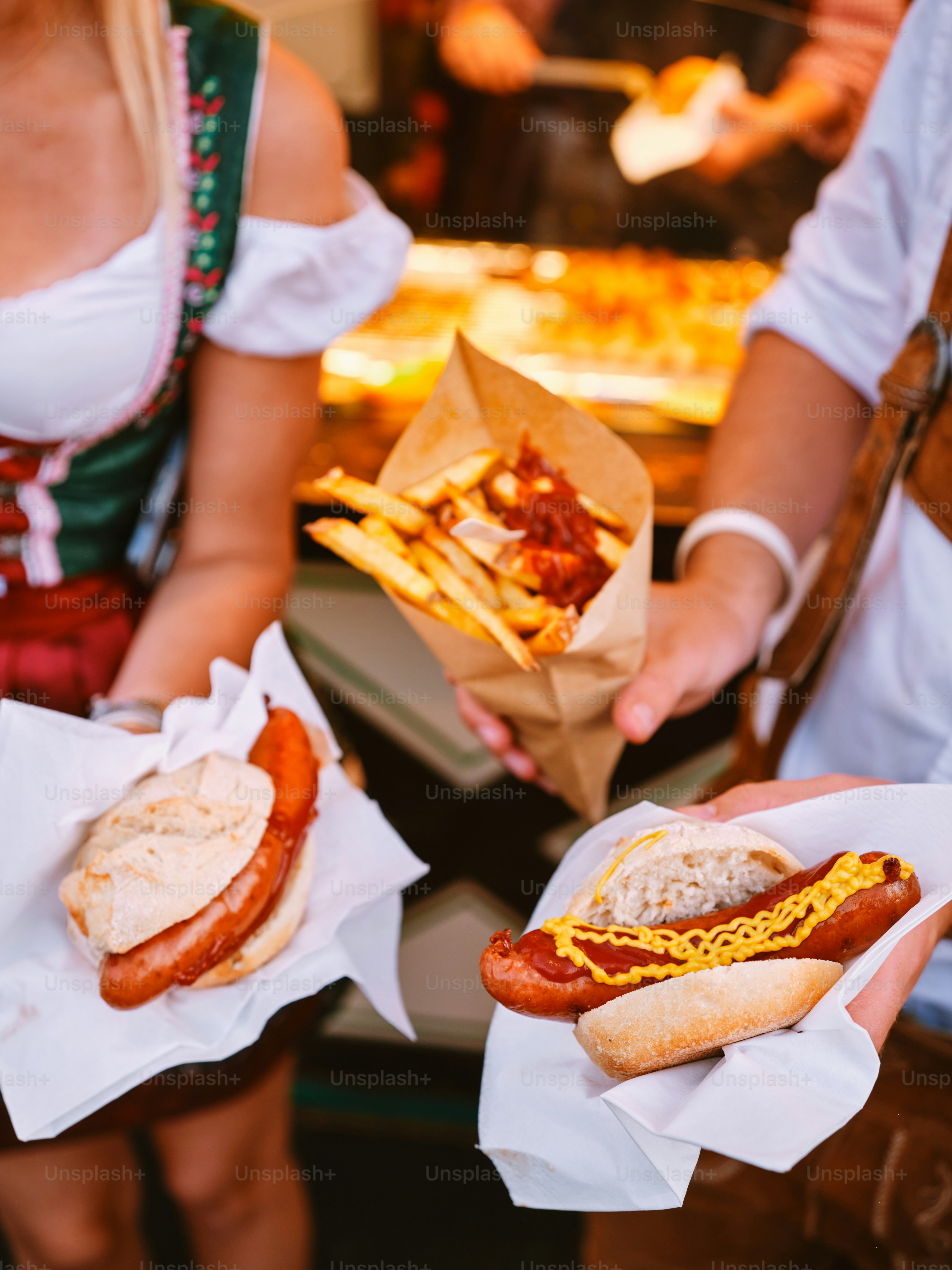 Un par de personas sosteniendo perros calientes y papas fritas foto ...