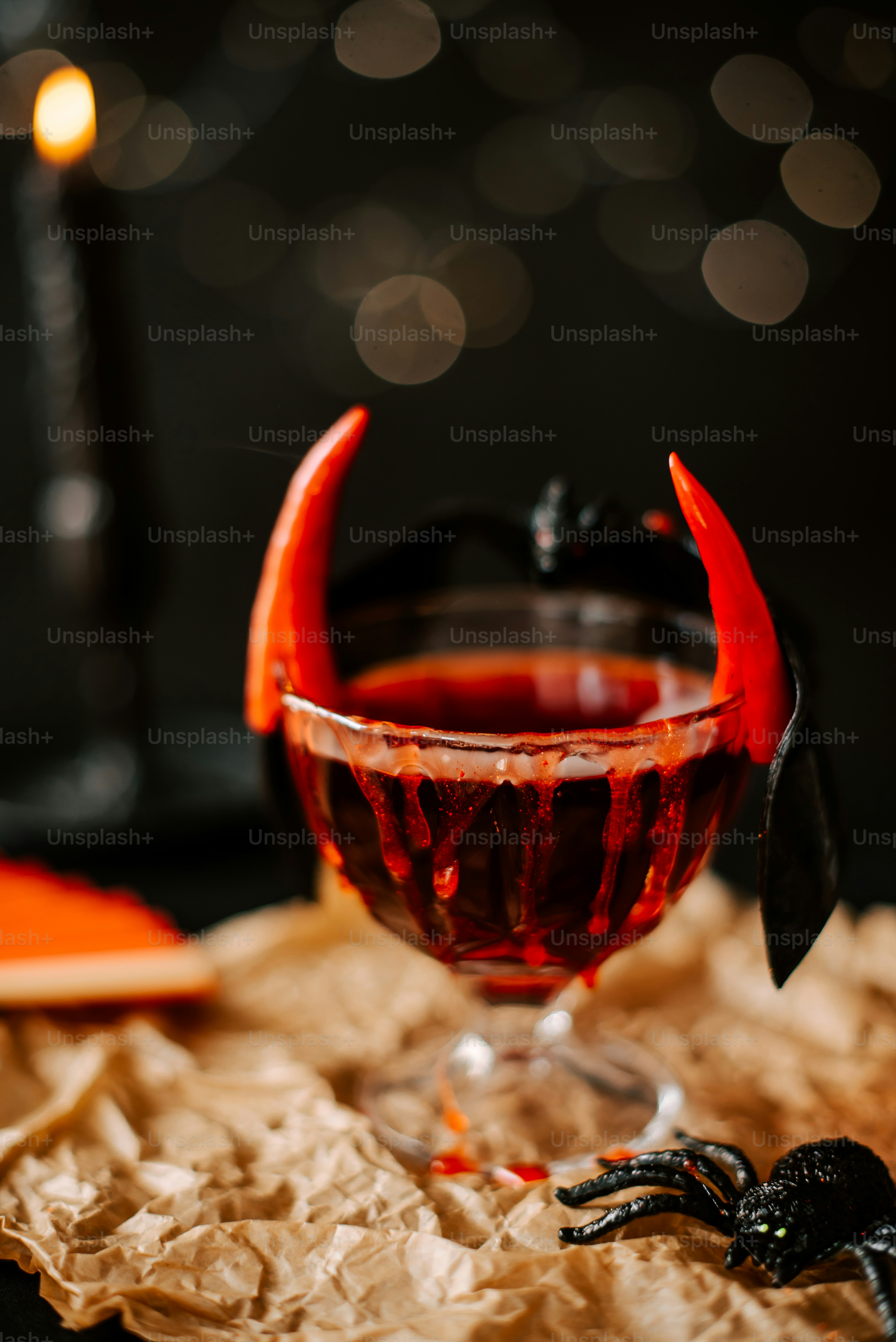 A glass of red liquid with a devil's head sticking out of it photo ...