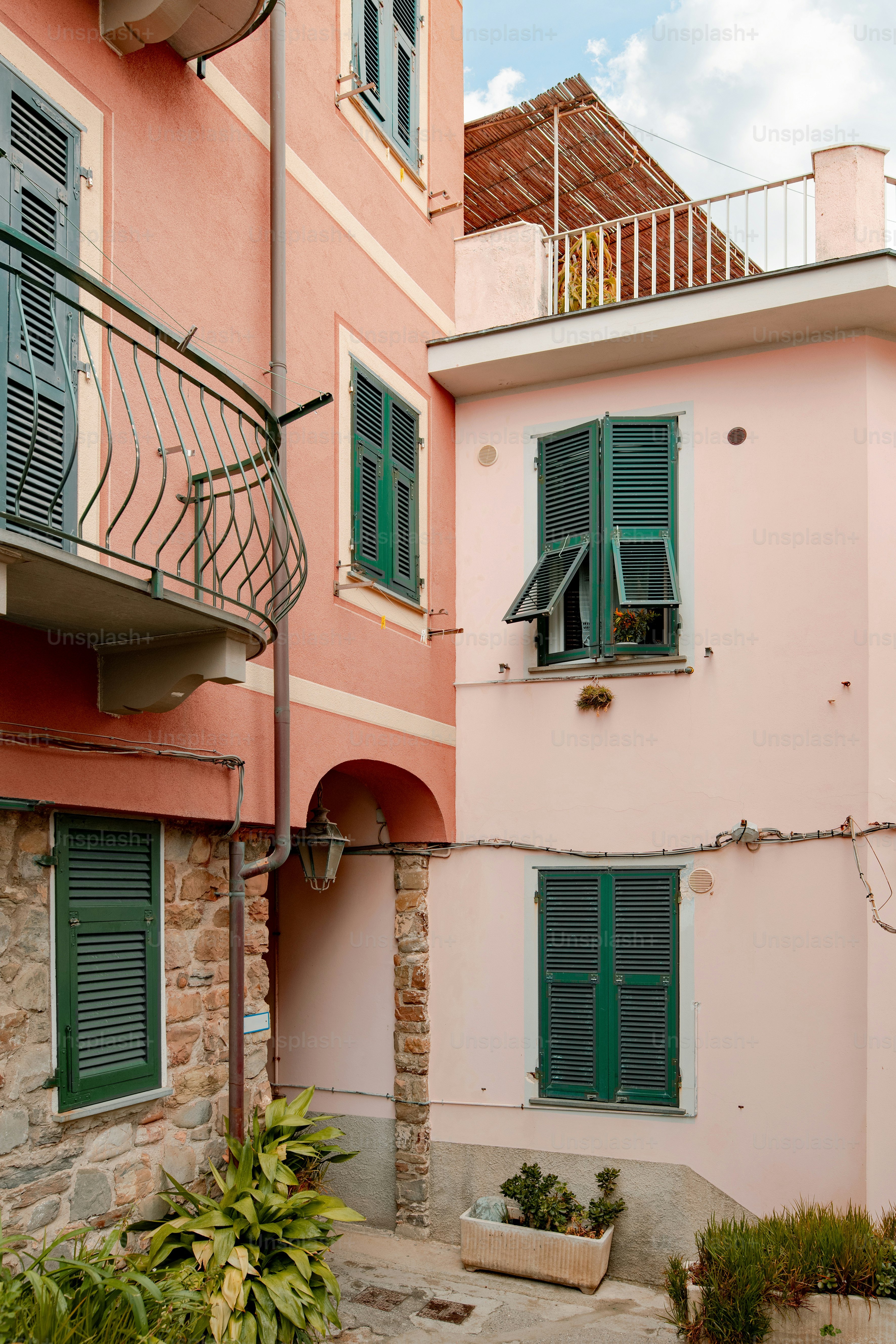 A pink building with green shutters and a balcony photo – Colorful ...