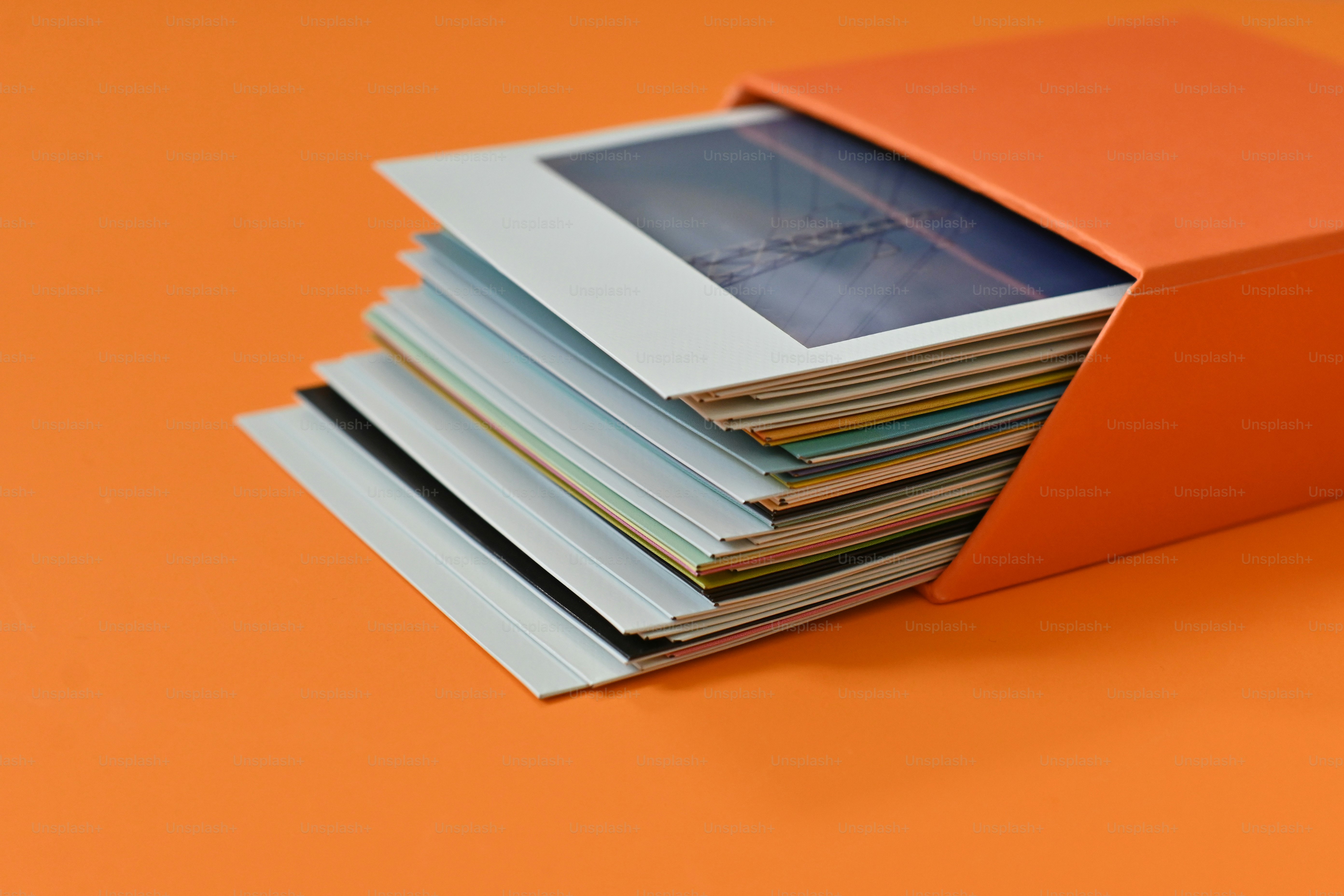 A stack of magazines sitting on top of an orange table photo – Polaroid ...