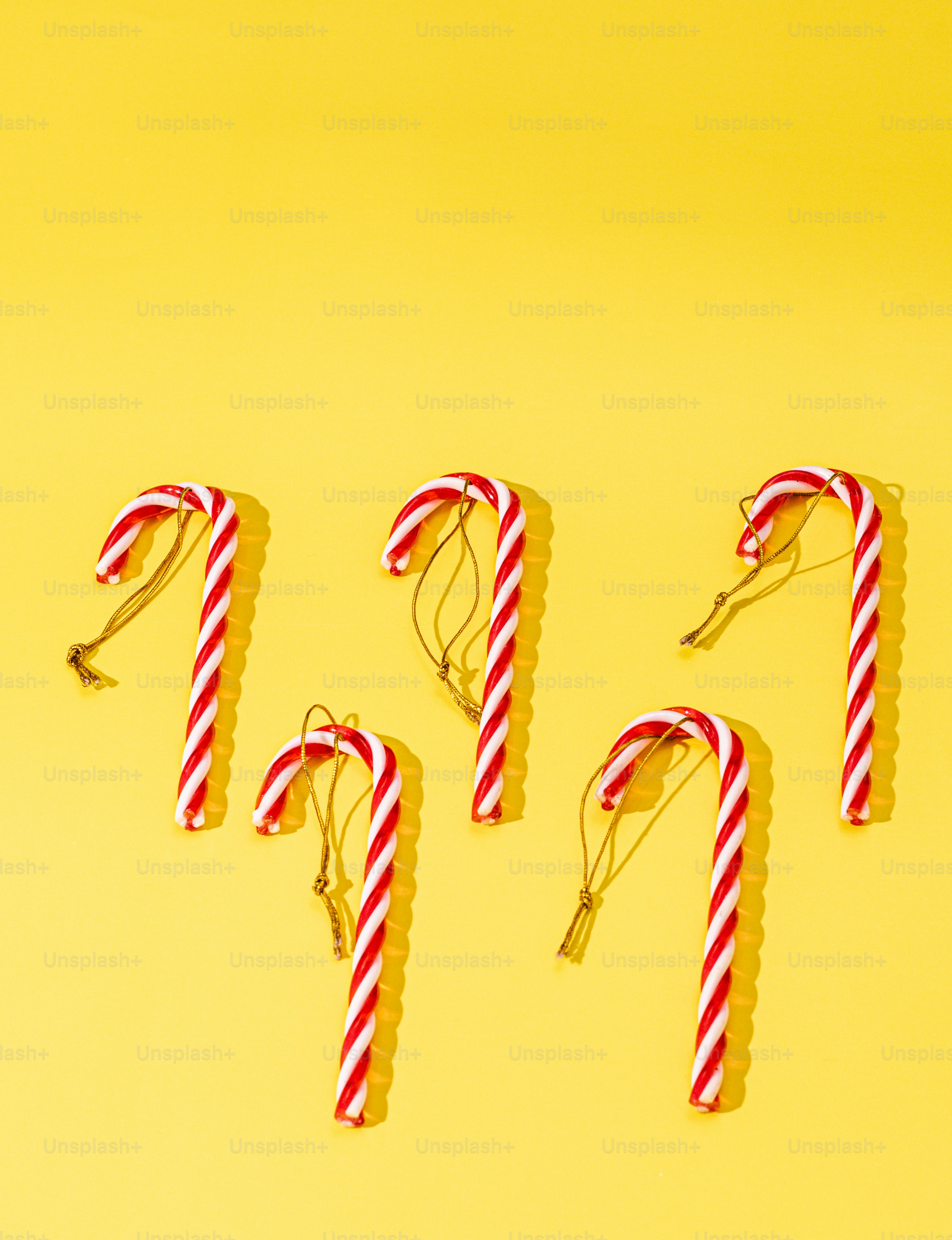 A group of candy canes sitting on top of a yellow surface photo ...
