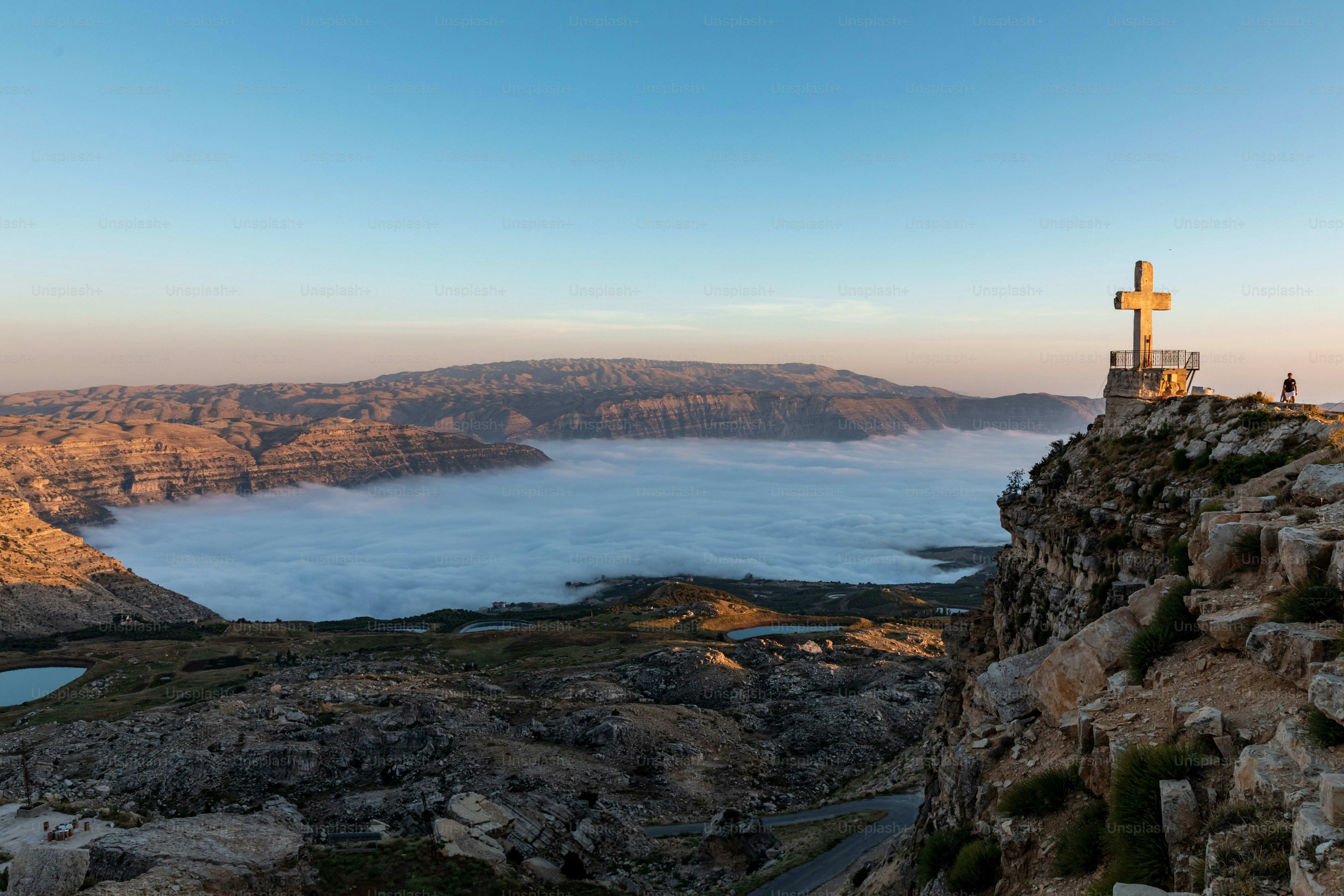 A landscape view of a cross on the rocks with clouds covering the ...