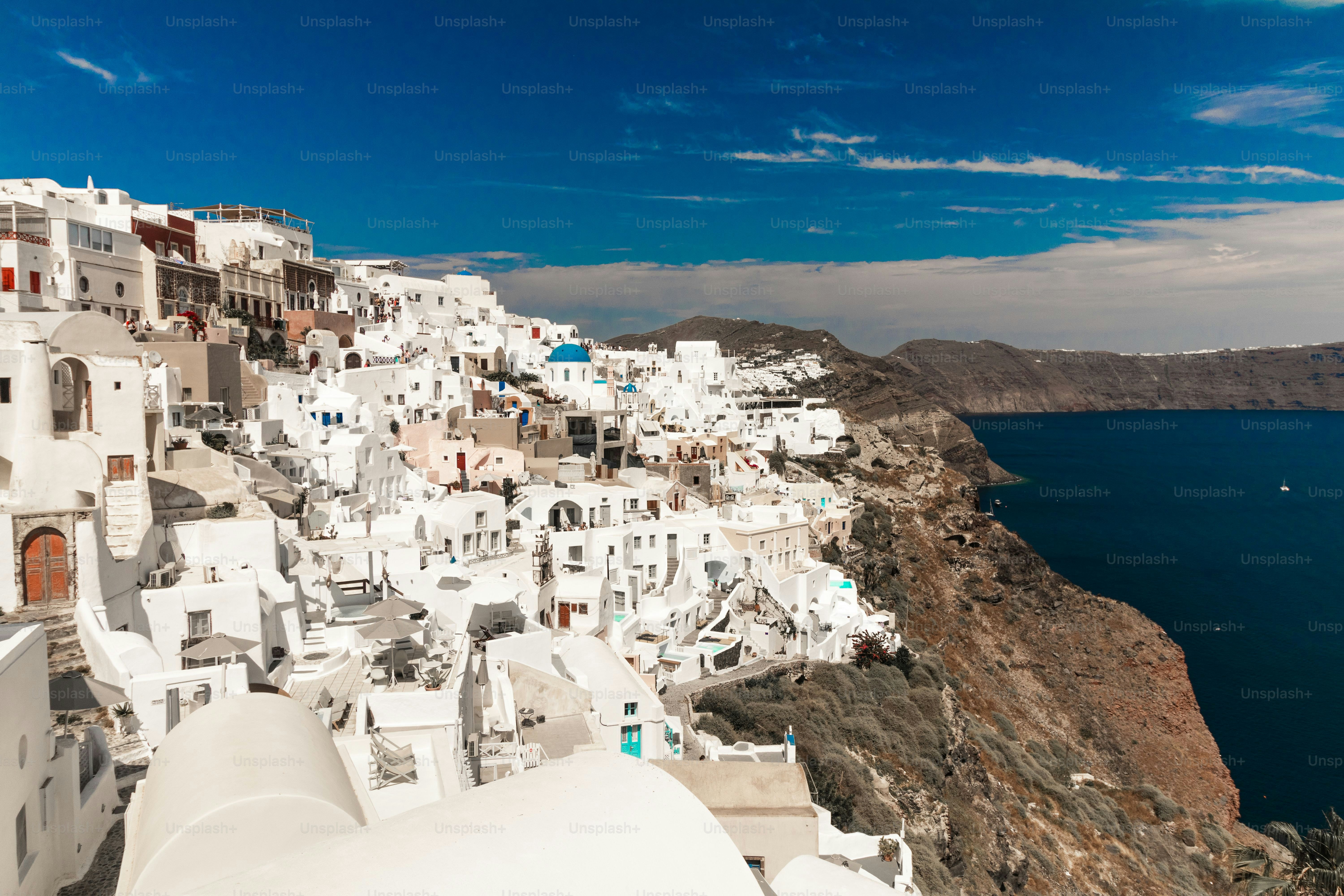 The beautiful view of traditional white Greek buildings on the cliffs ...