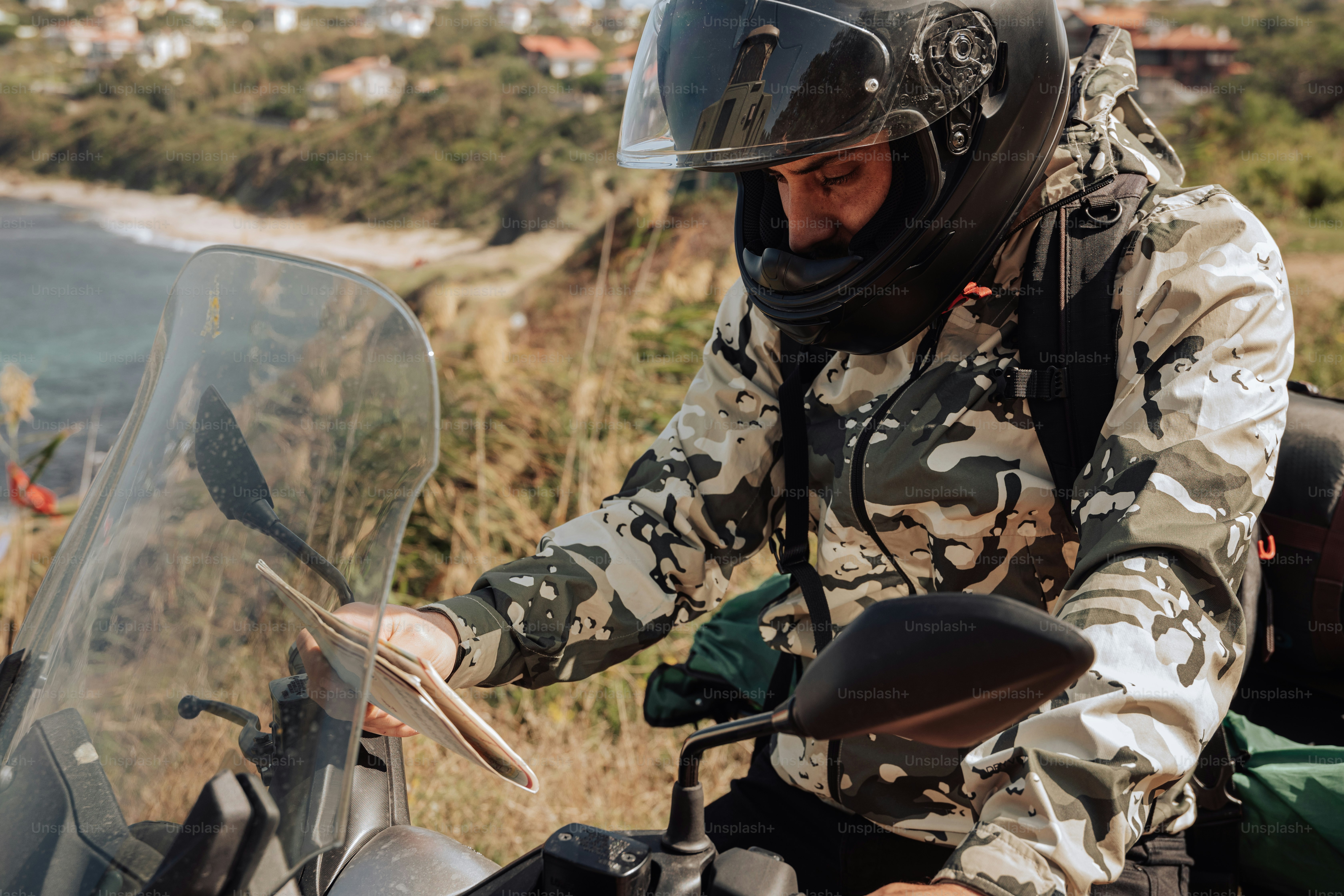A man riding a motorcycle on top of a lush green hillside photo – Range ...