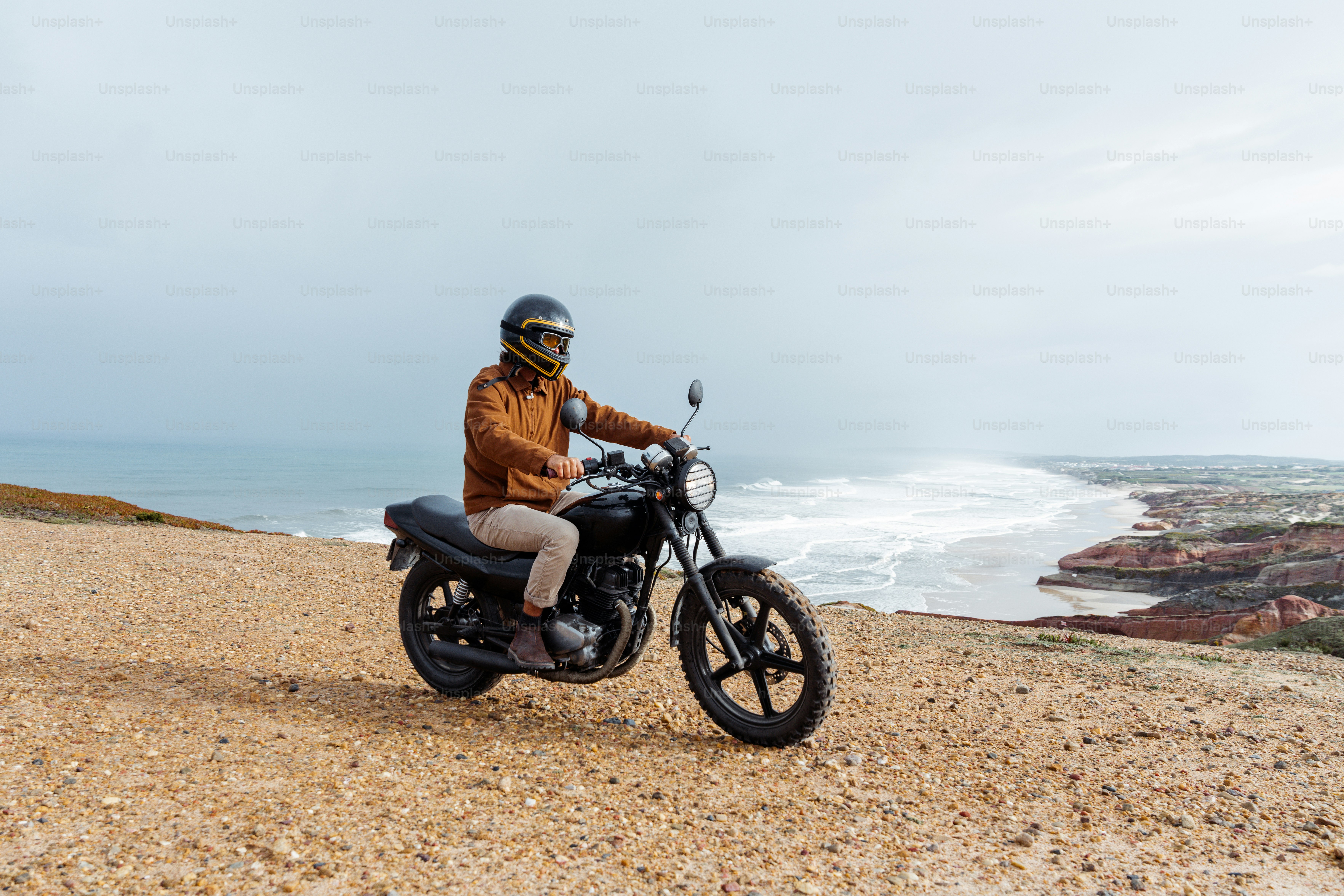 A man riding a motorcycle on top of a sandy beach photo – Travel Image ...