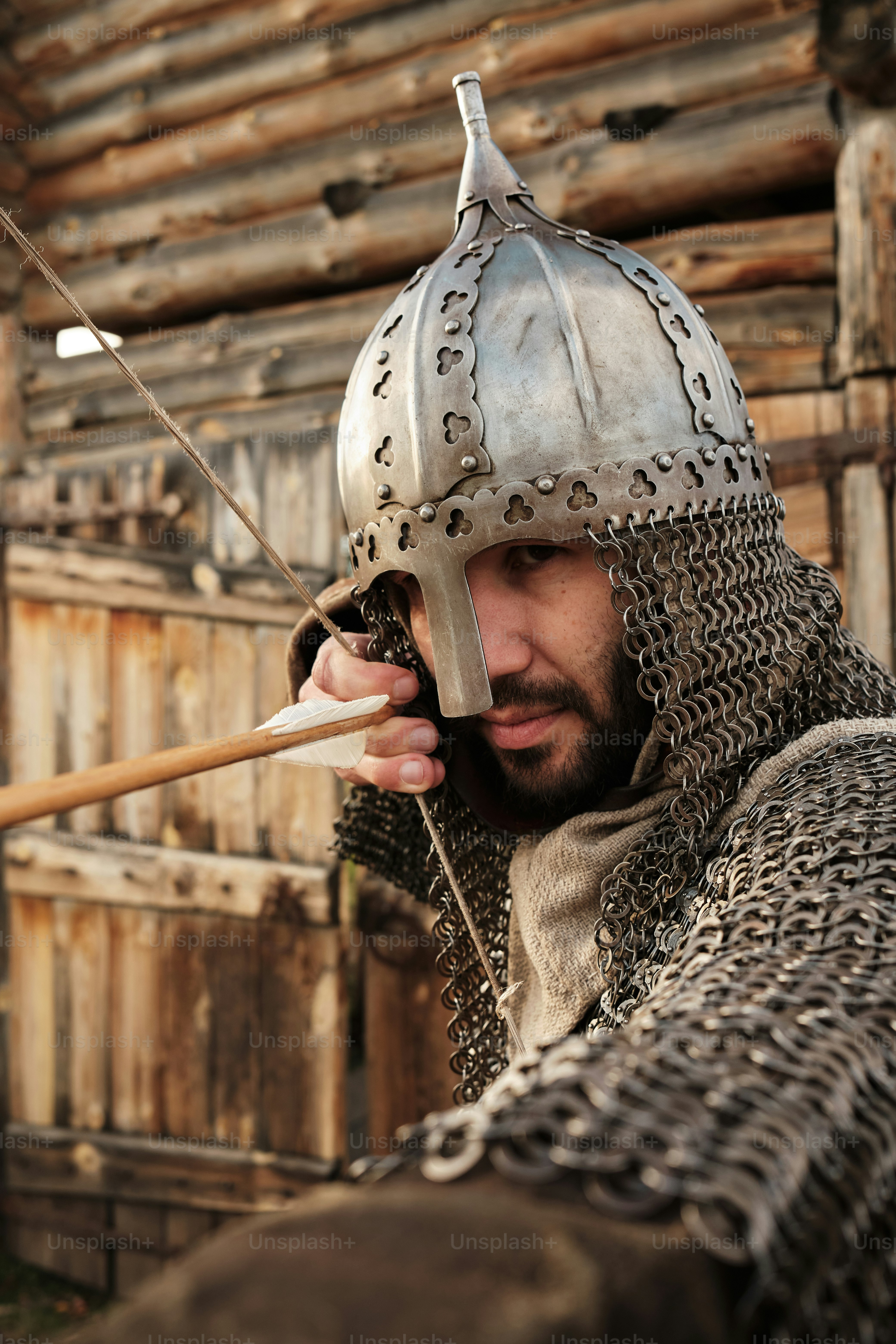 A man in a chain mail outfit holding a wooden stick photo – Archer ...