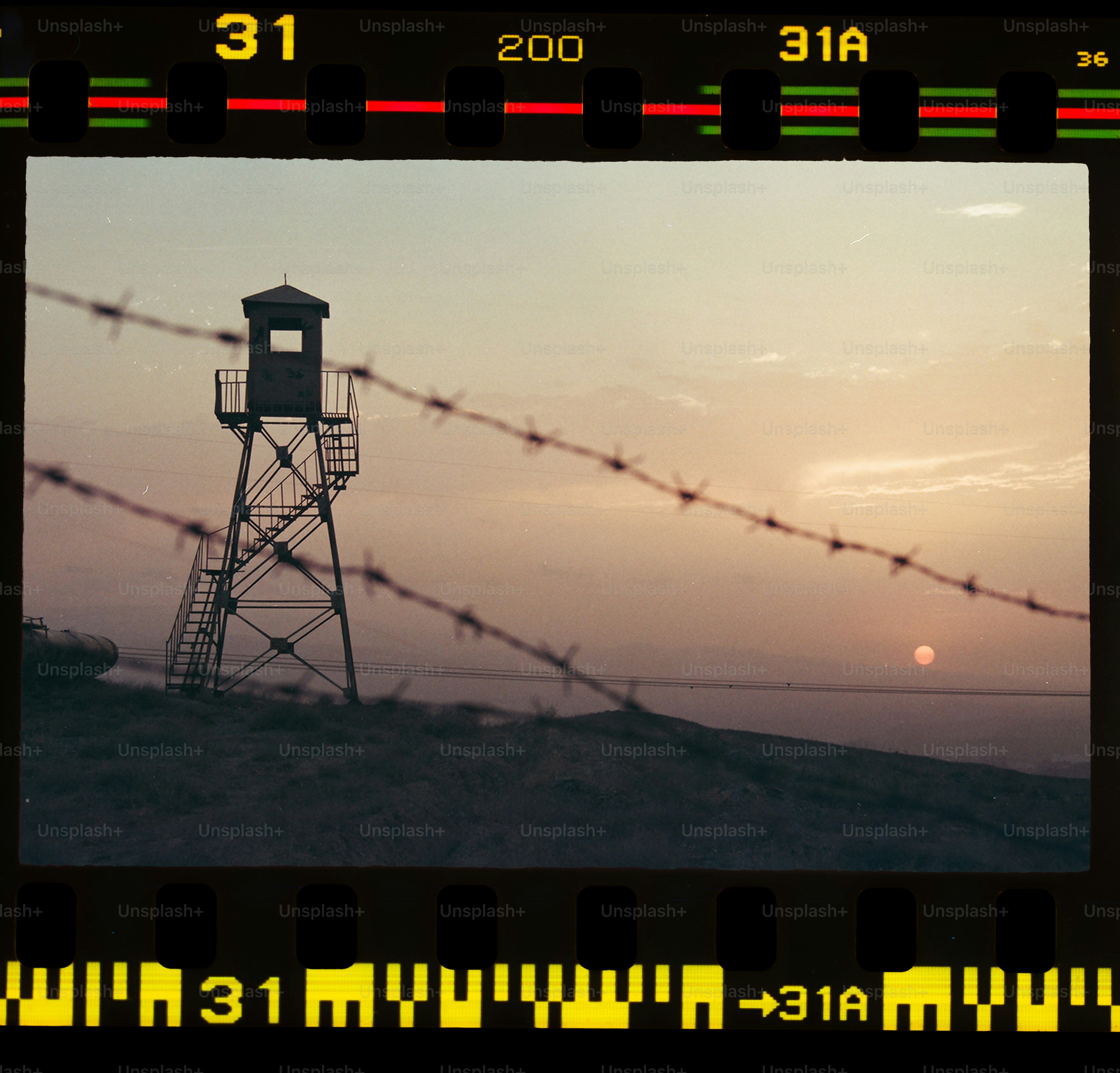 A picture of a tower behind a barbed wire fence photo – Image Image on ...