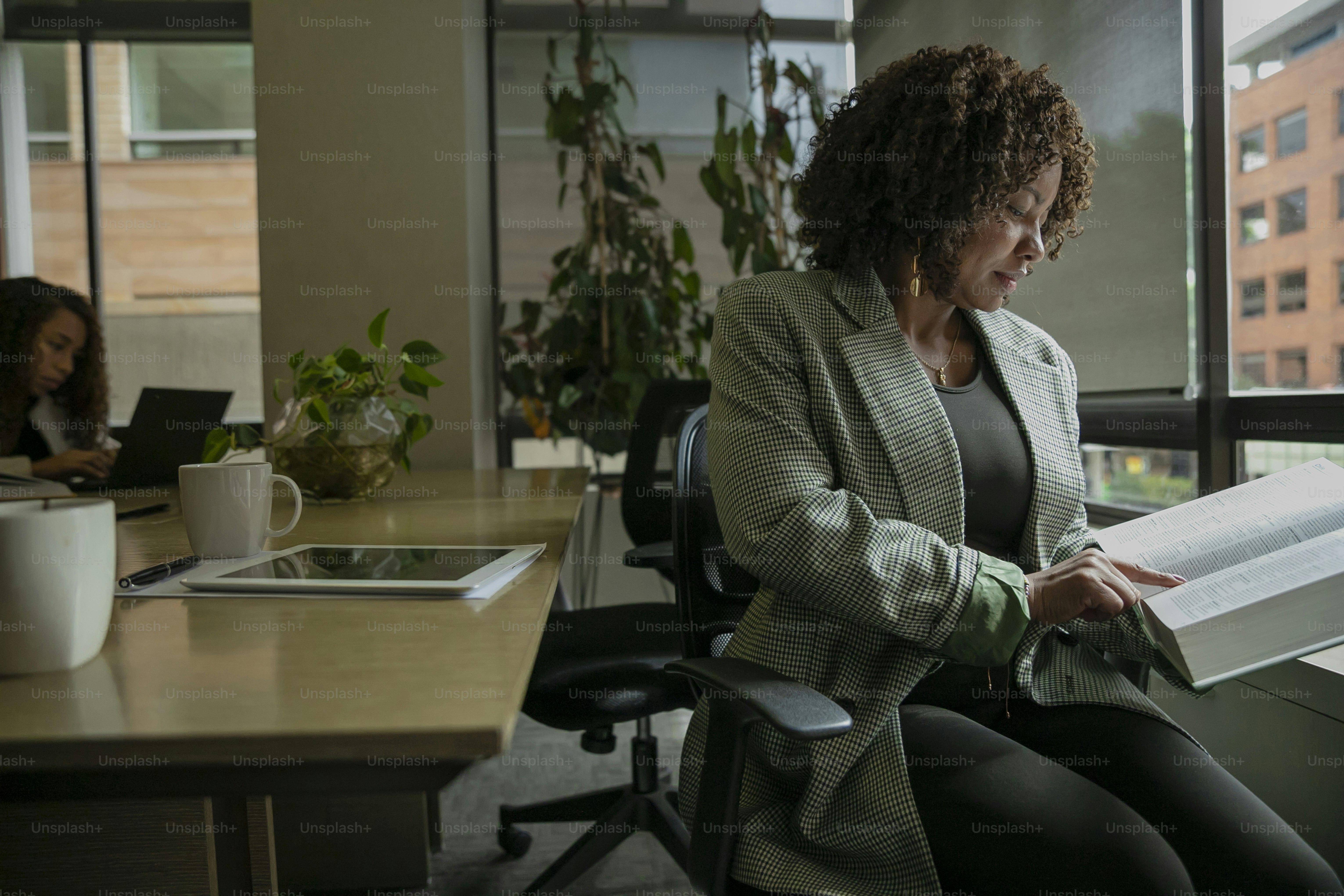 A woman sitting at a desk reading a book photo – Indoors Image on Unsplash