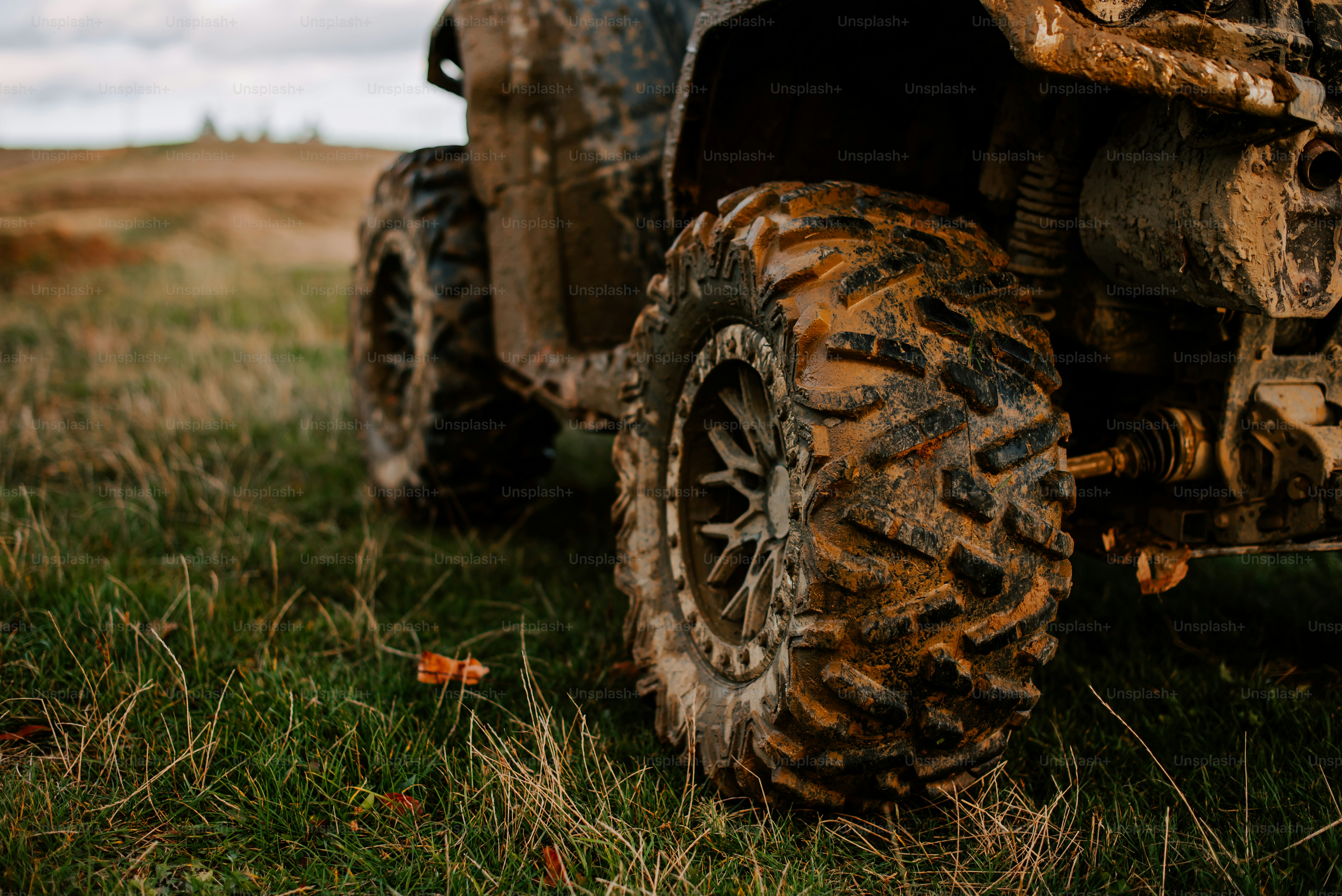A muddy four wheeler parked in a grassy field photo – Adventure Image ...