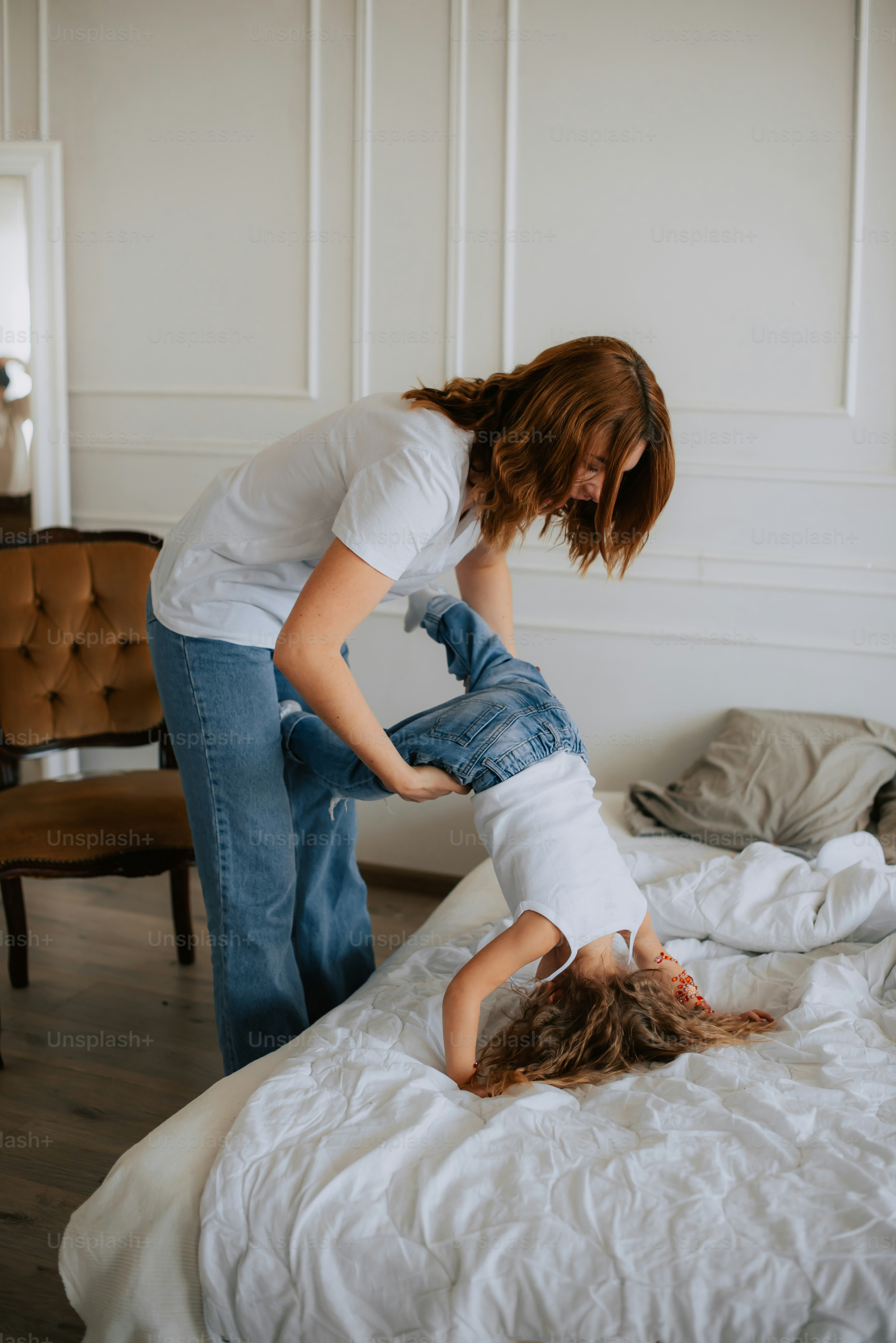 A woman standing over another woman laying on a bed photo – Parenting ...