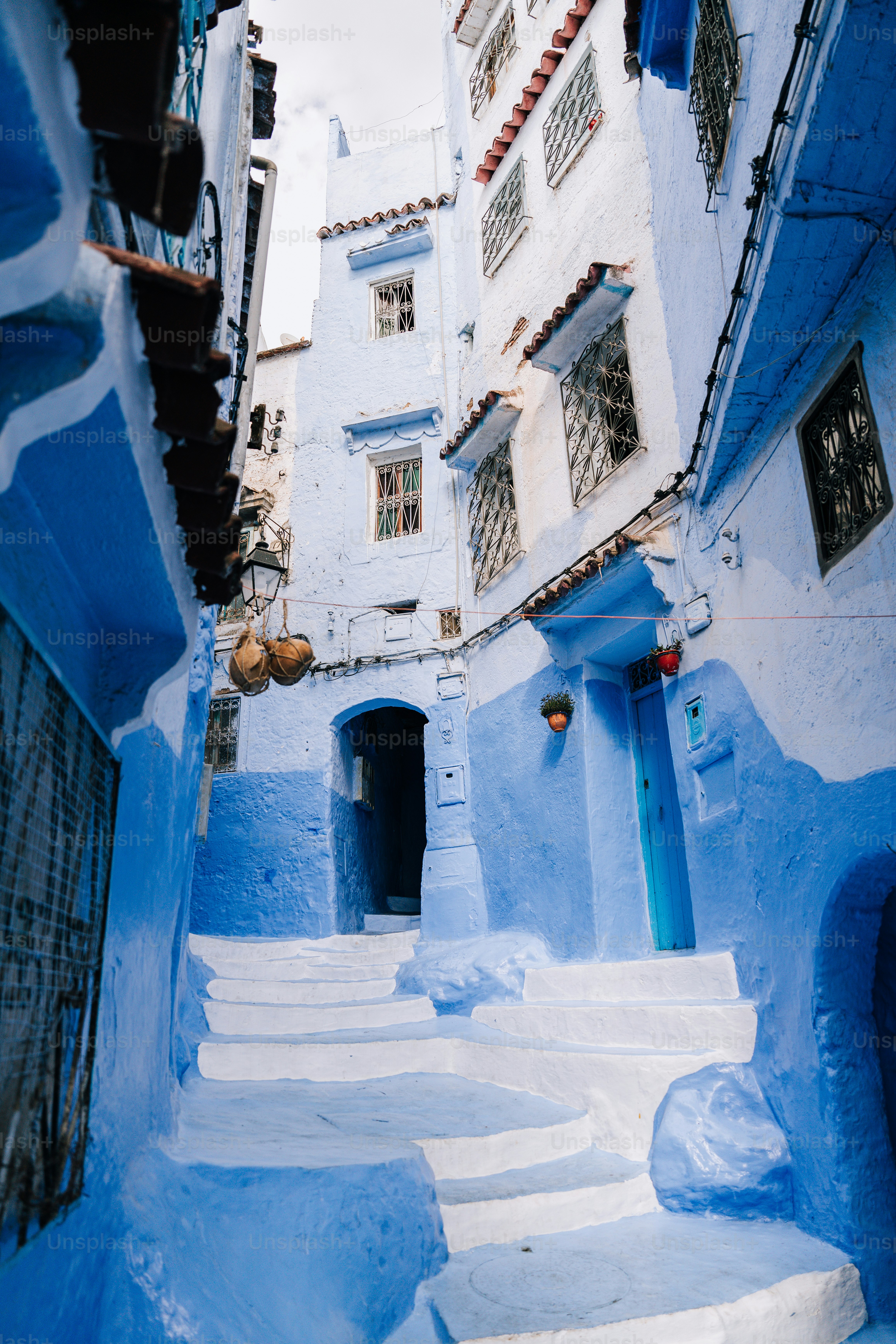 A narrow alleyway with blue walls and potted plants photo – Walls Image ...