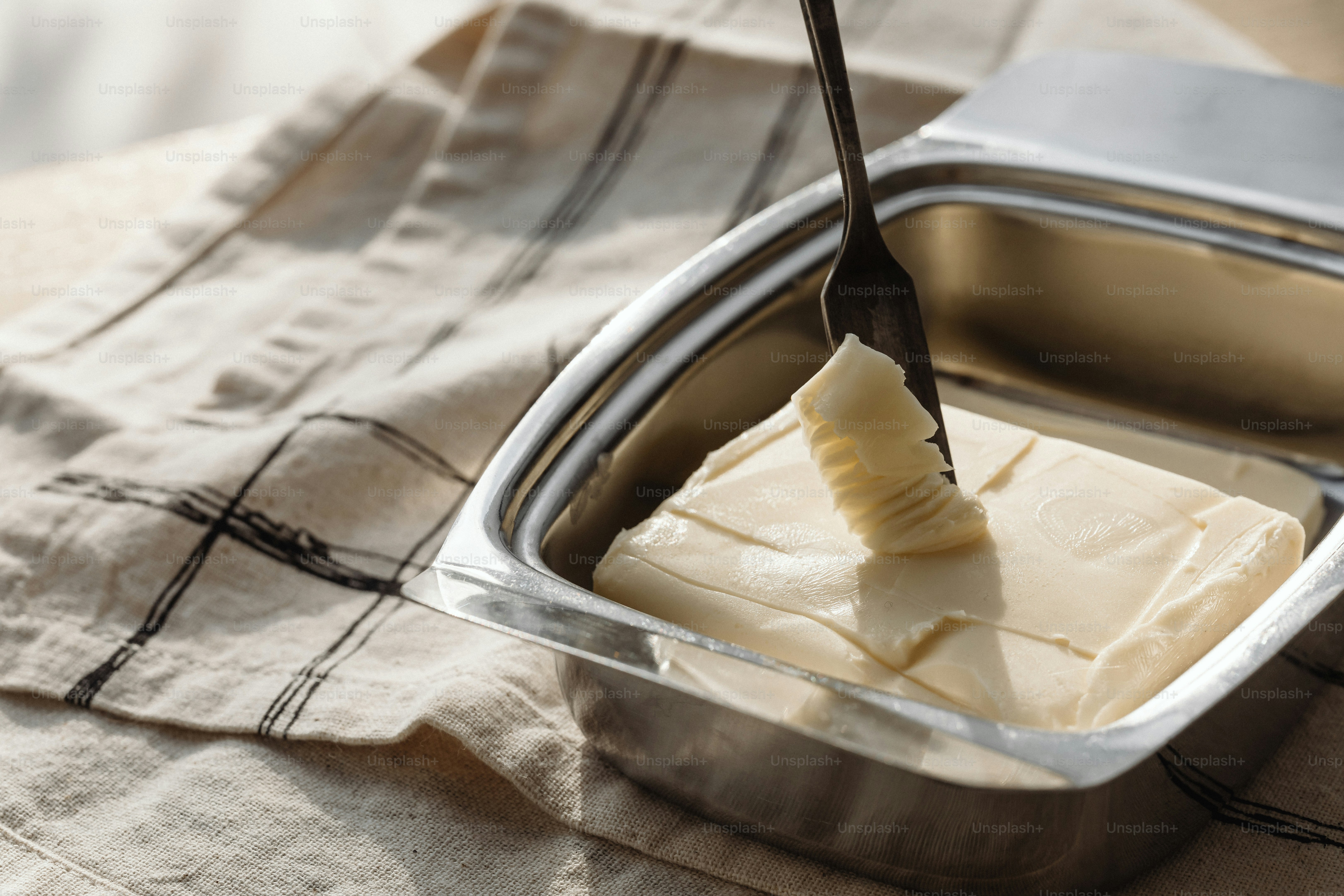 A piece of butter in a metal container with a spoon photo – Food Image ...