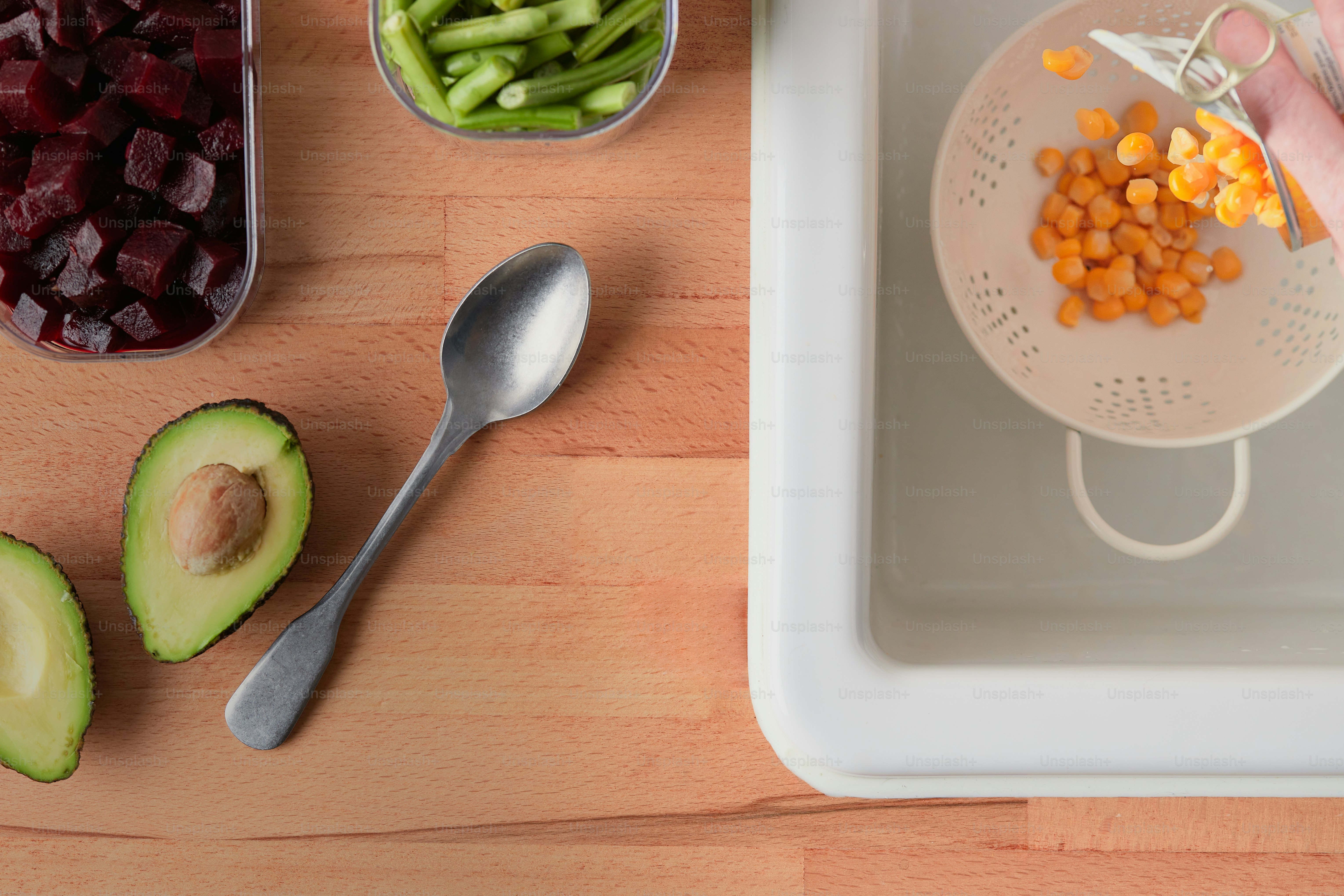 A person scooping vegetables into a bowl with a spoon photo – Food ...
