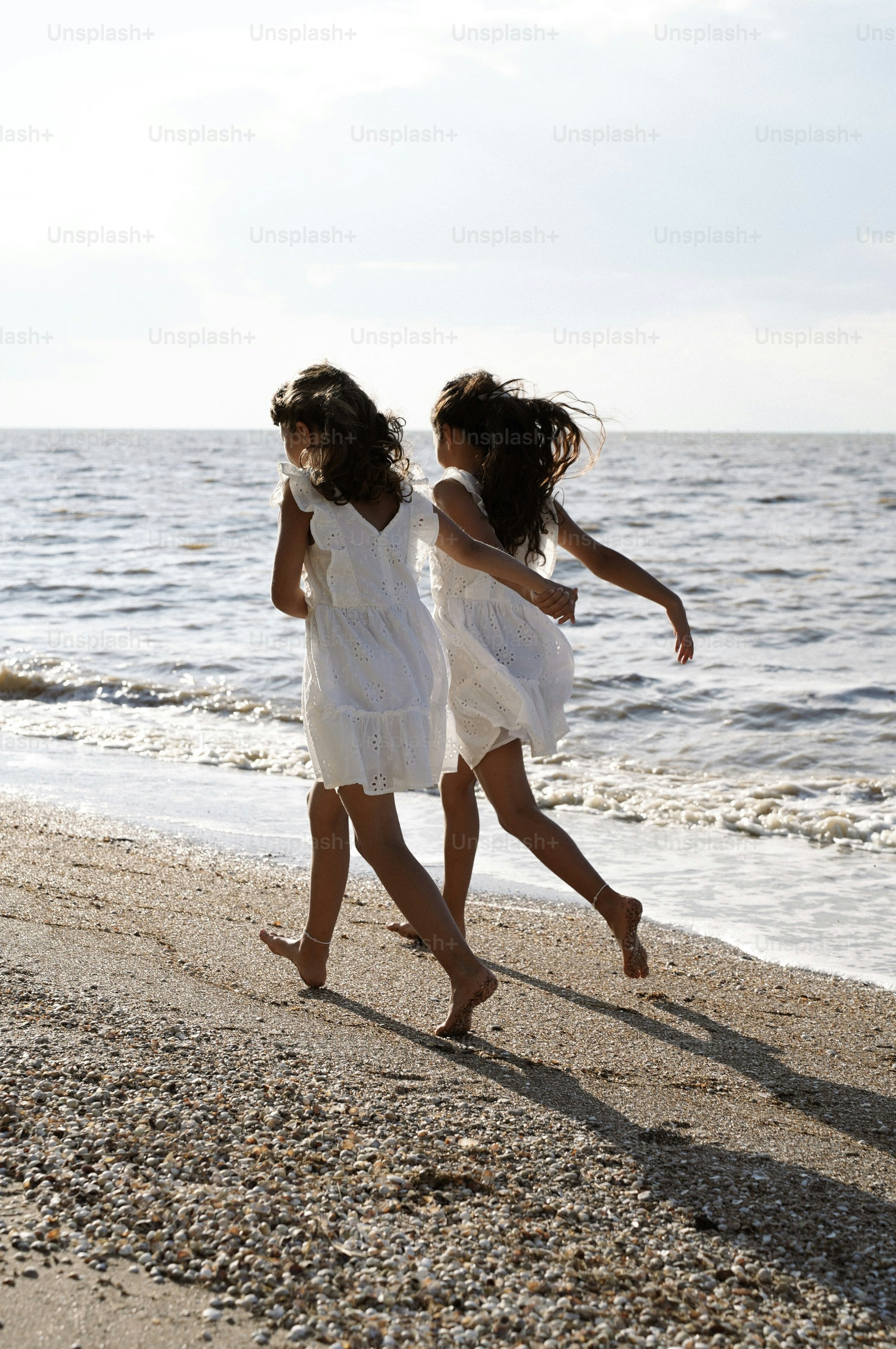 Two young girls run along the beach towards the water photo – Russia ...
