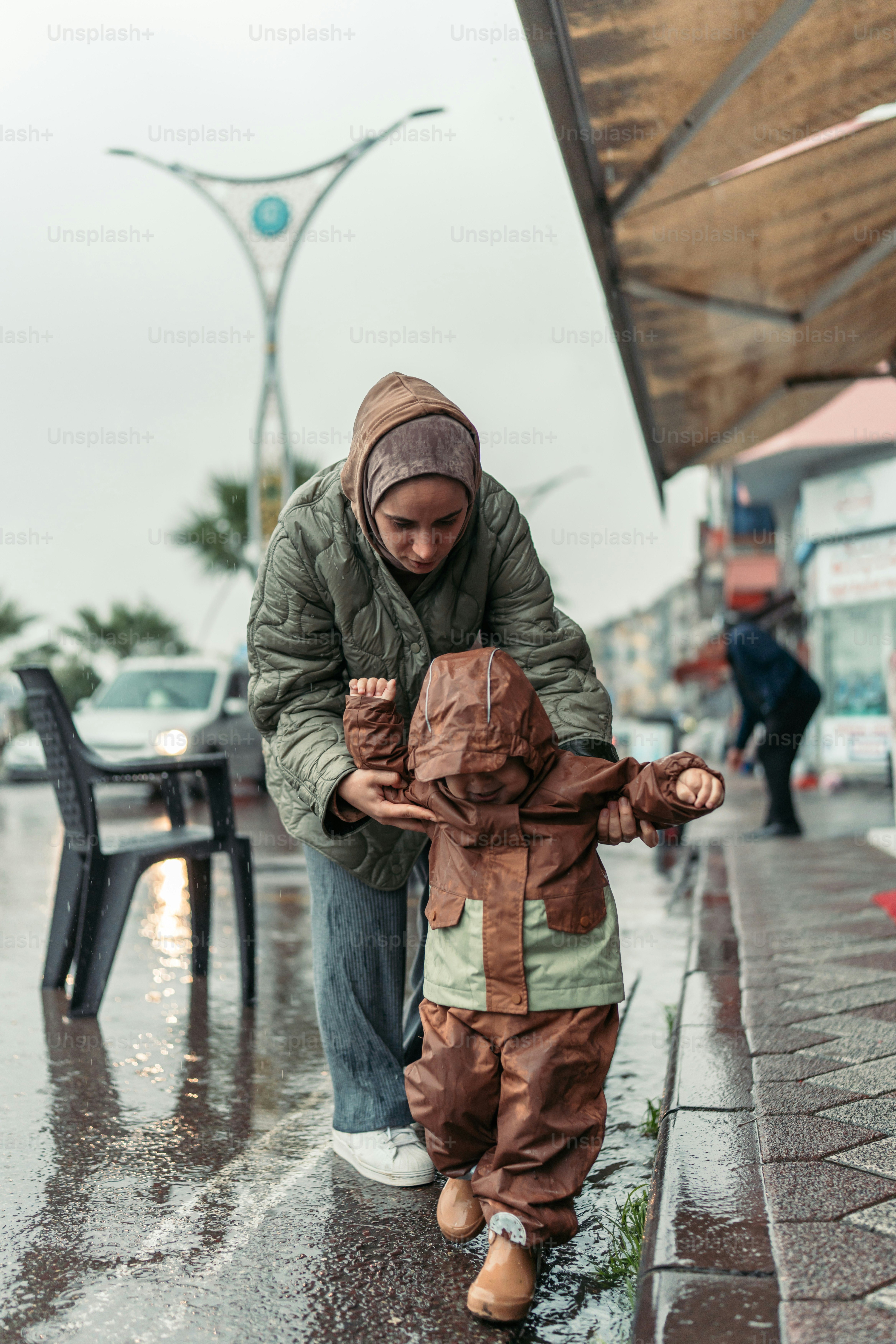 A man helping a child walk down the sidewalk photo – Family Image on ...