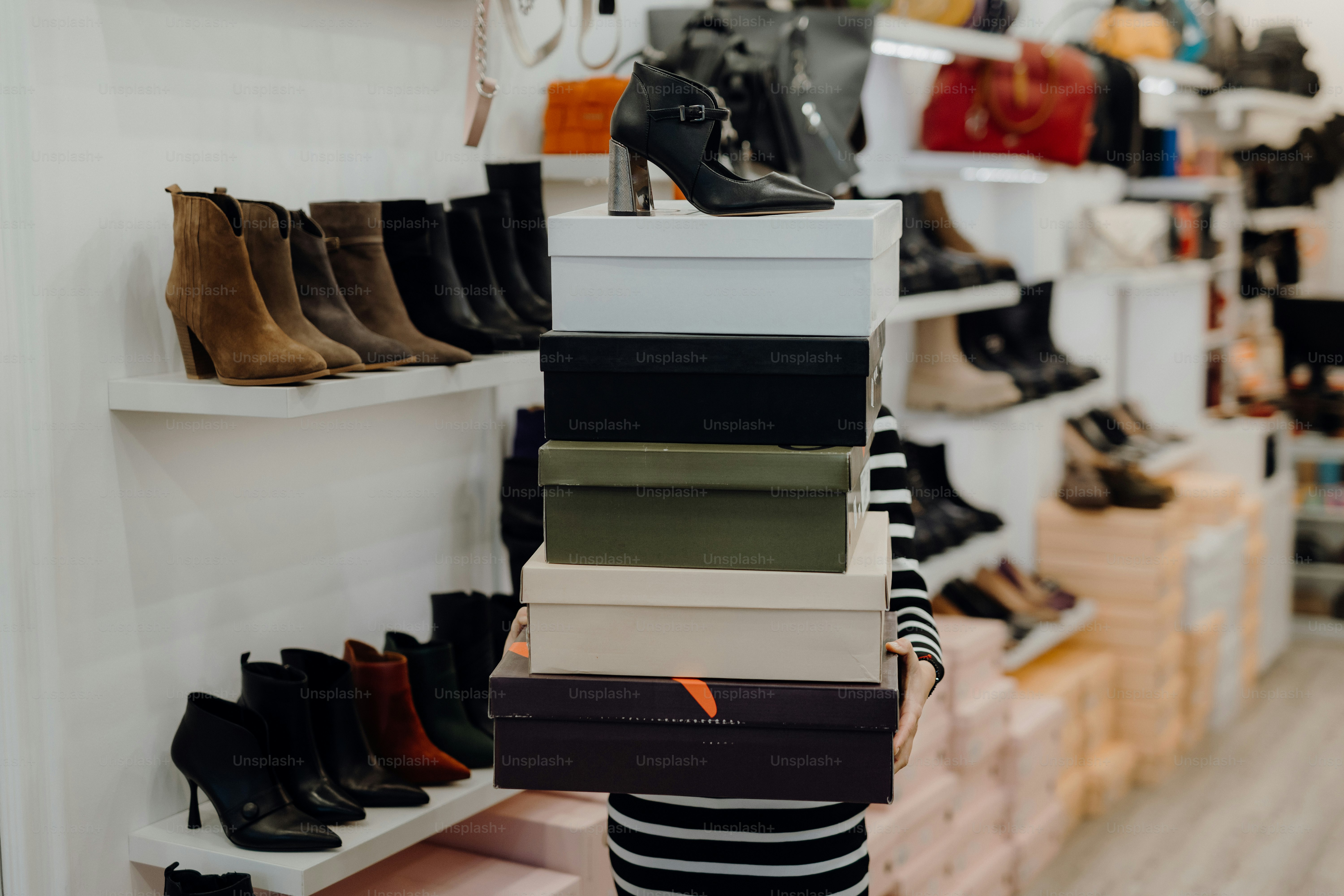 A woman holding a stack of shoes in a shoe store photo – Black friday ...