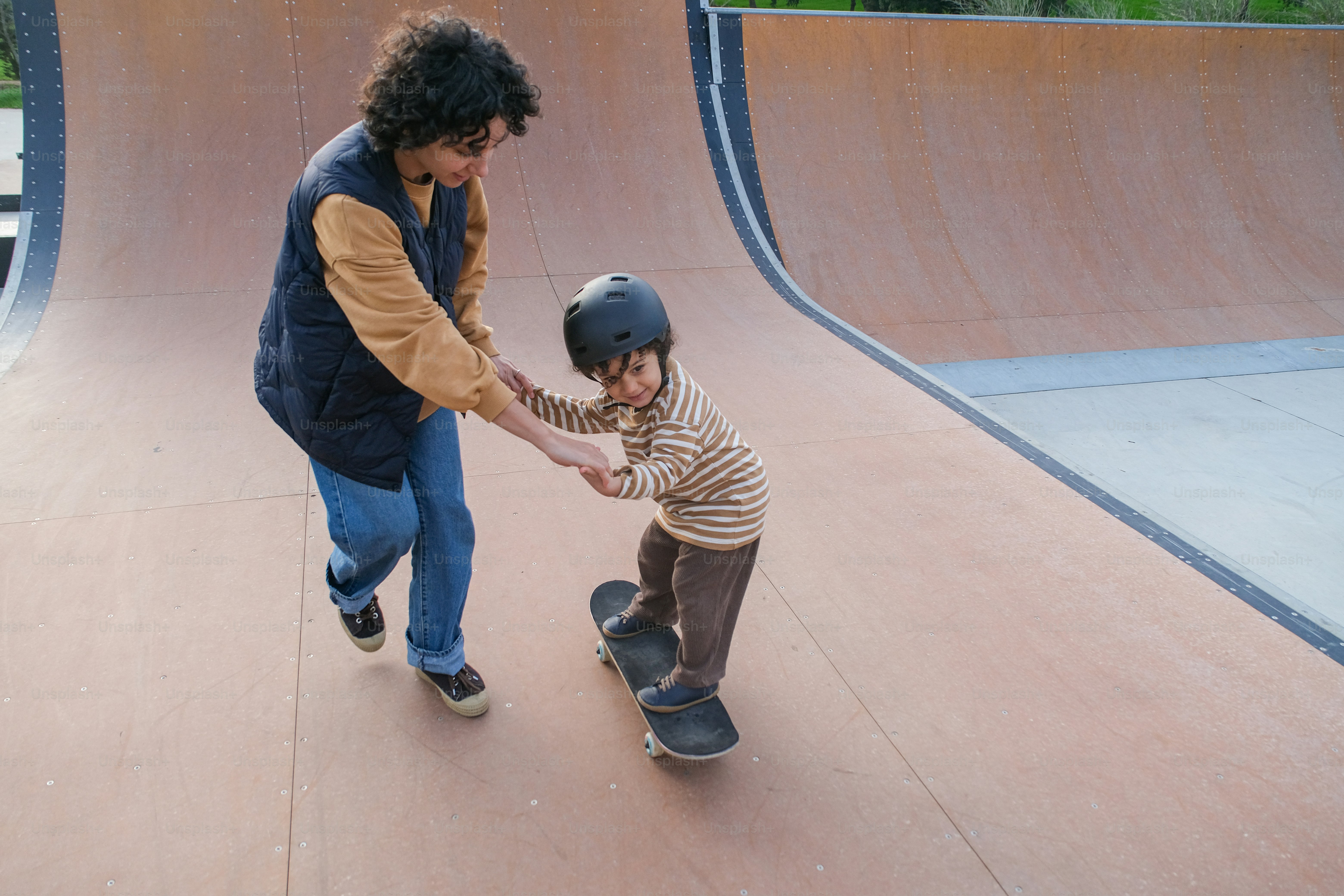 A man helping a child ride a skateboard on a ramp photo – Family Image ...