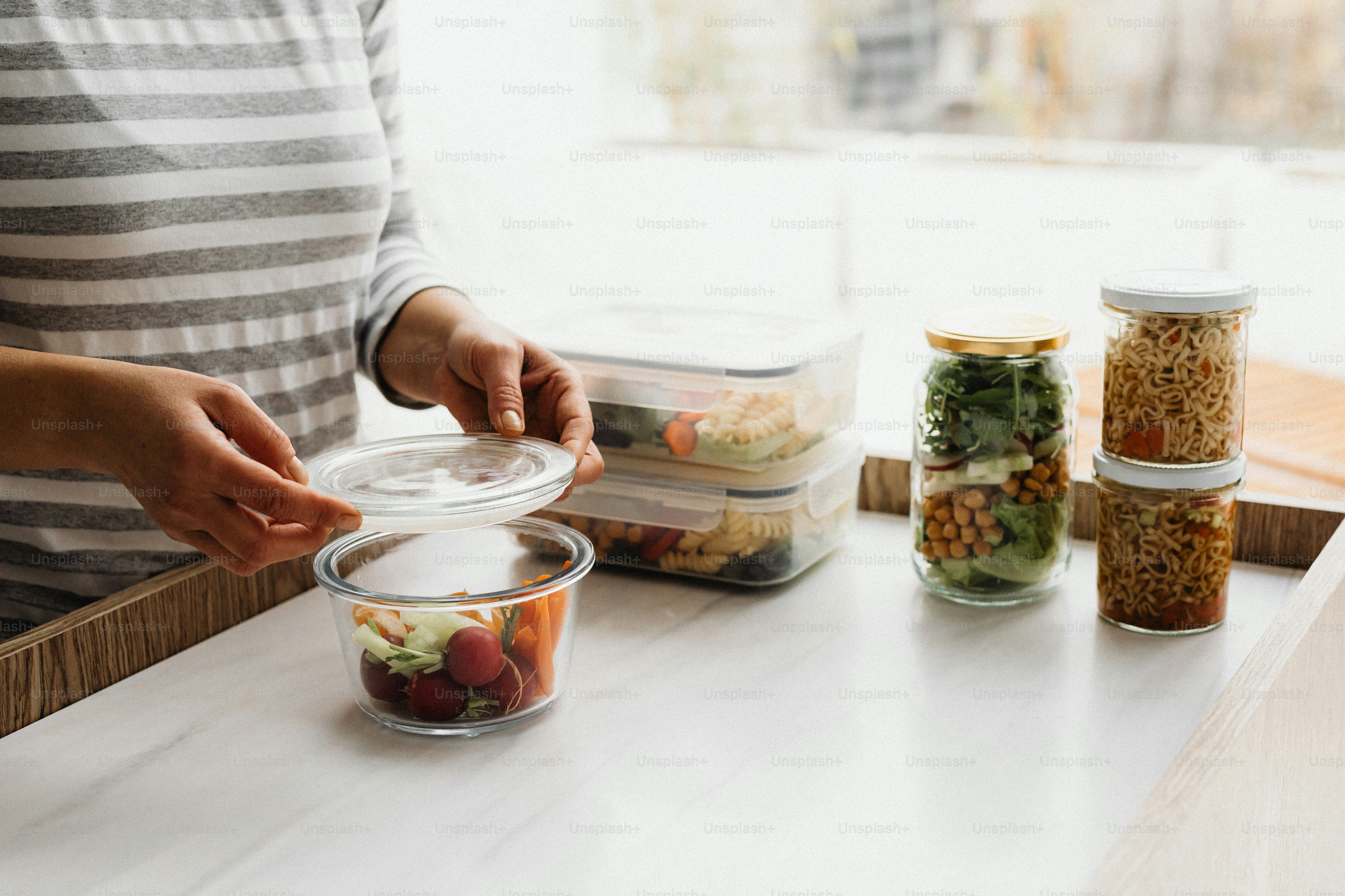 A person putting a container of food into a container photo – Meal ...