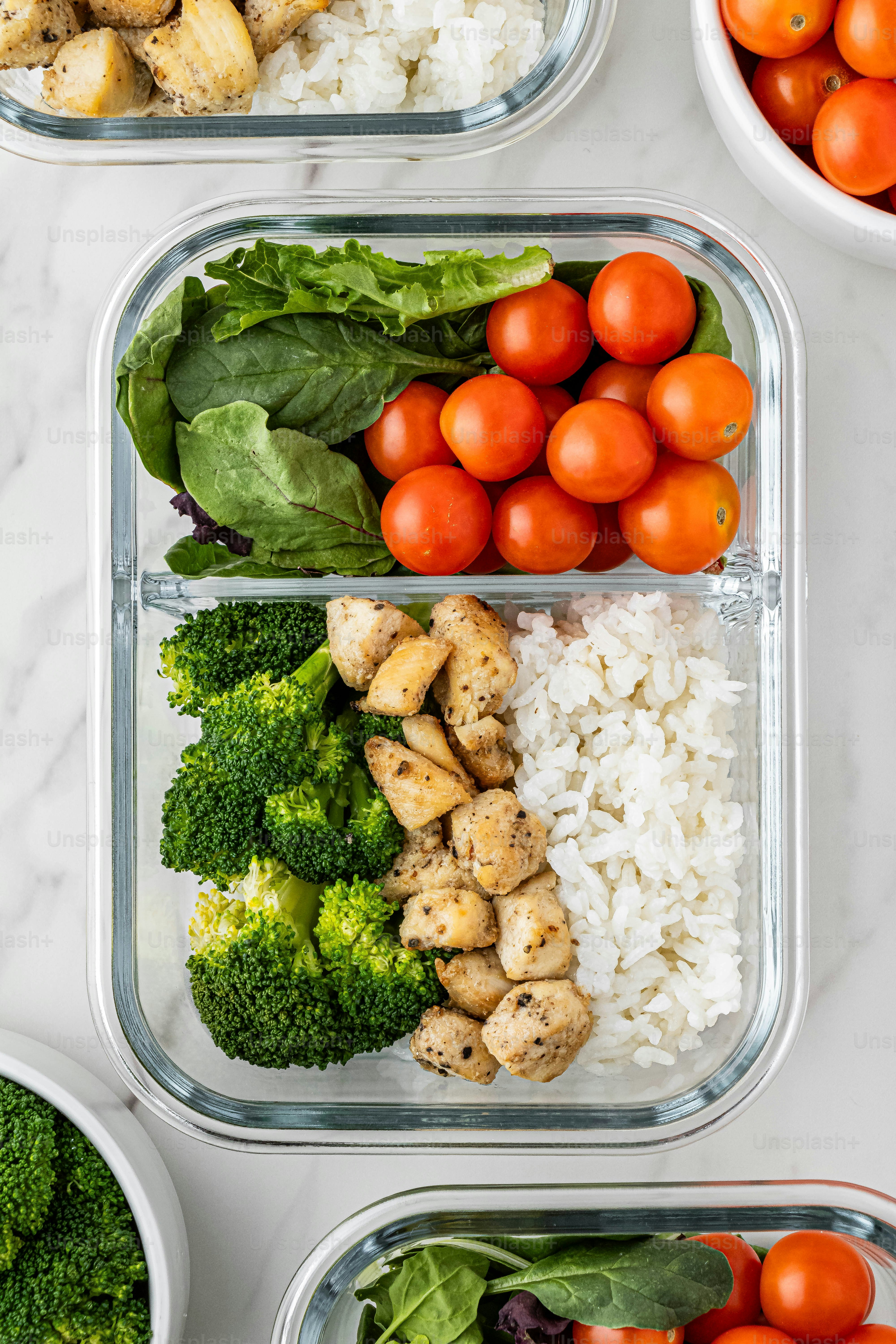 Four containers of food containing rice, broccoli, tomatoes, and ...