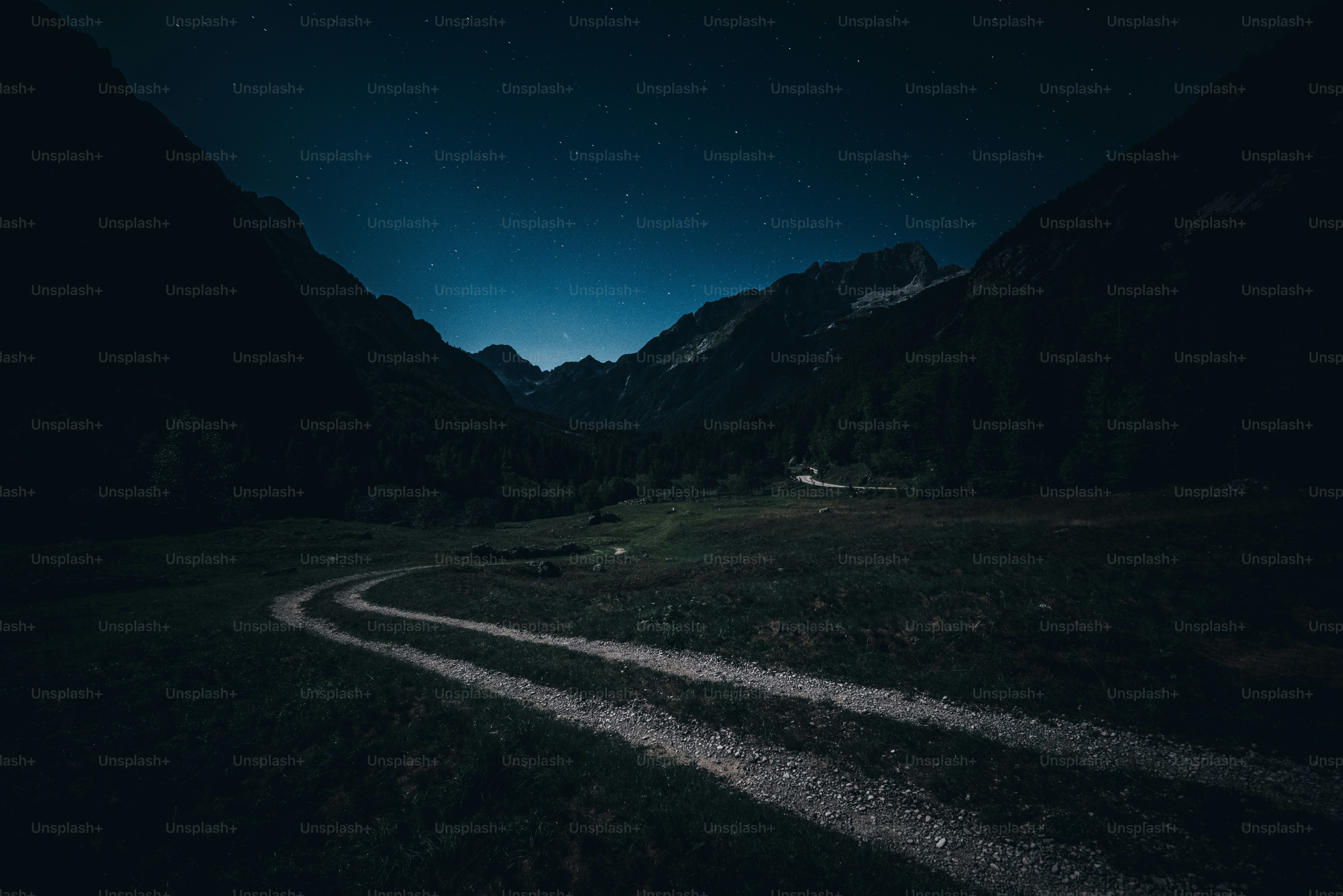 A dirt road in the middle of a mountain at night photo – Landscape ...