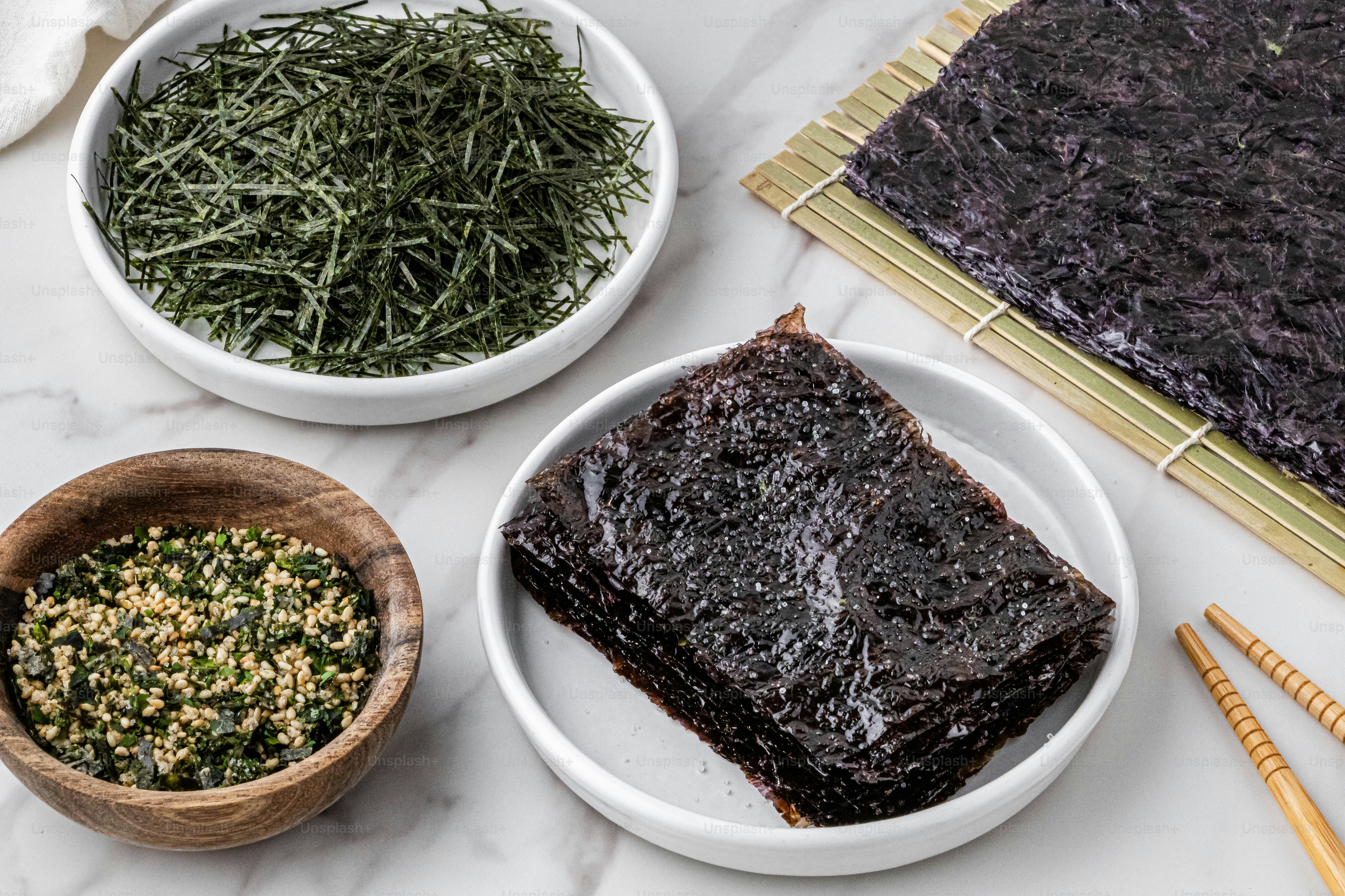 A table topped with plates of food and bowls of greens photo – Nori ...