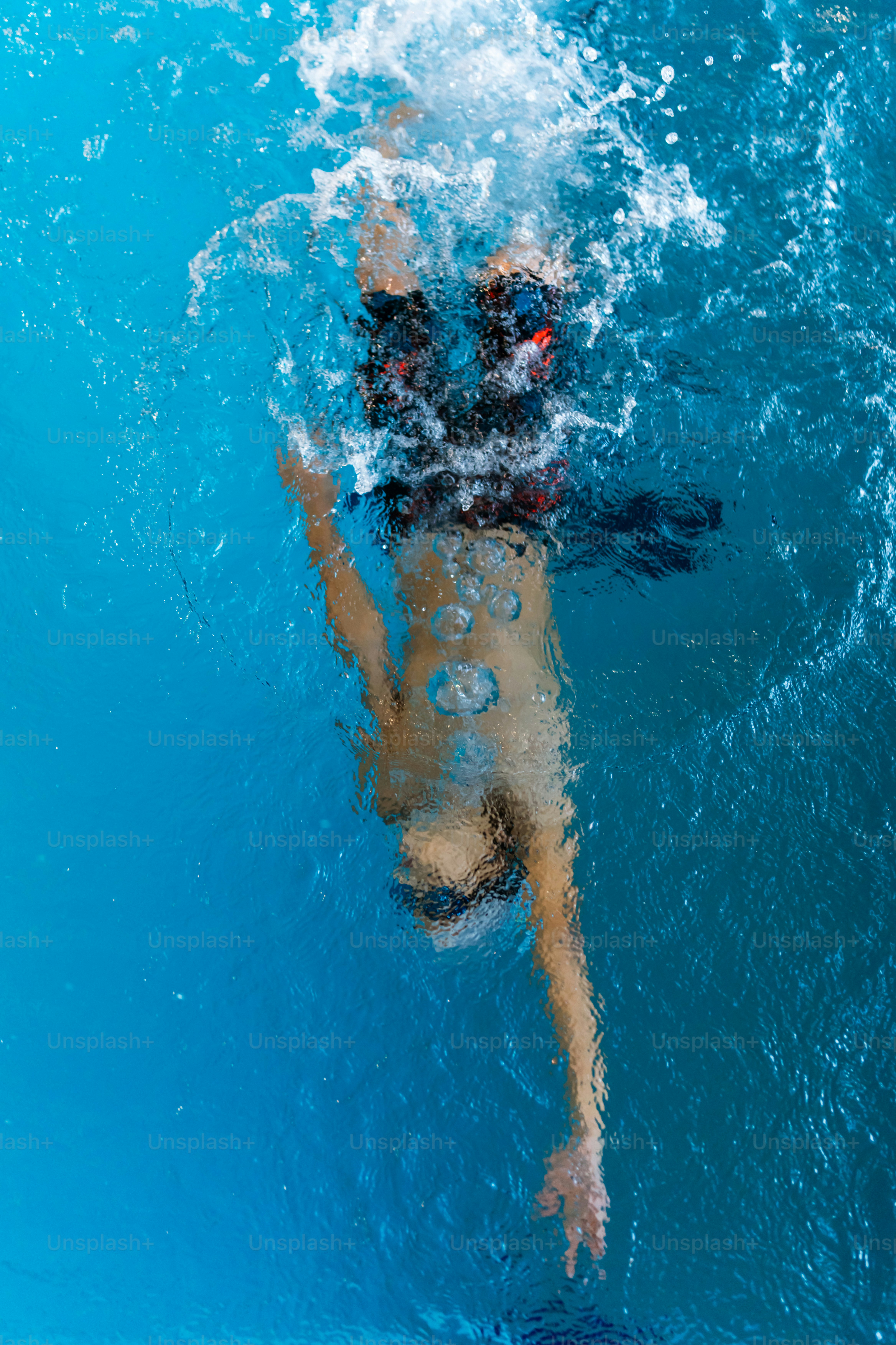 A person swimming in a pool with a frisbee photo – Swimmer Image on ...