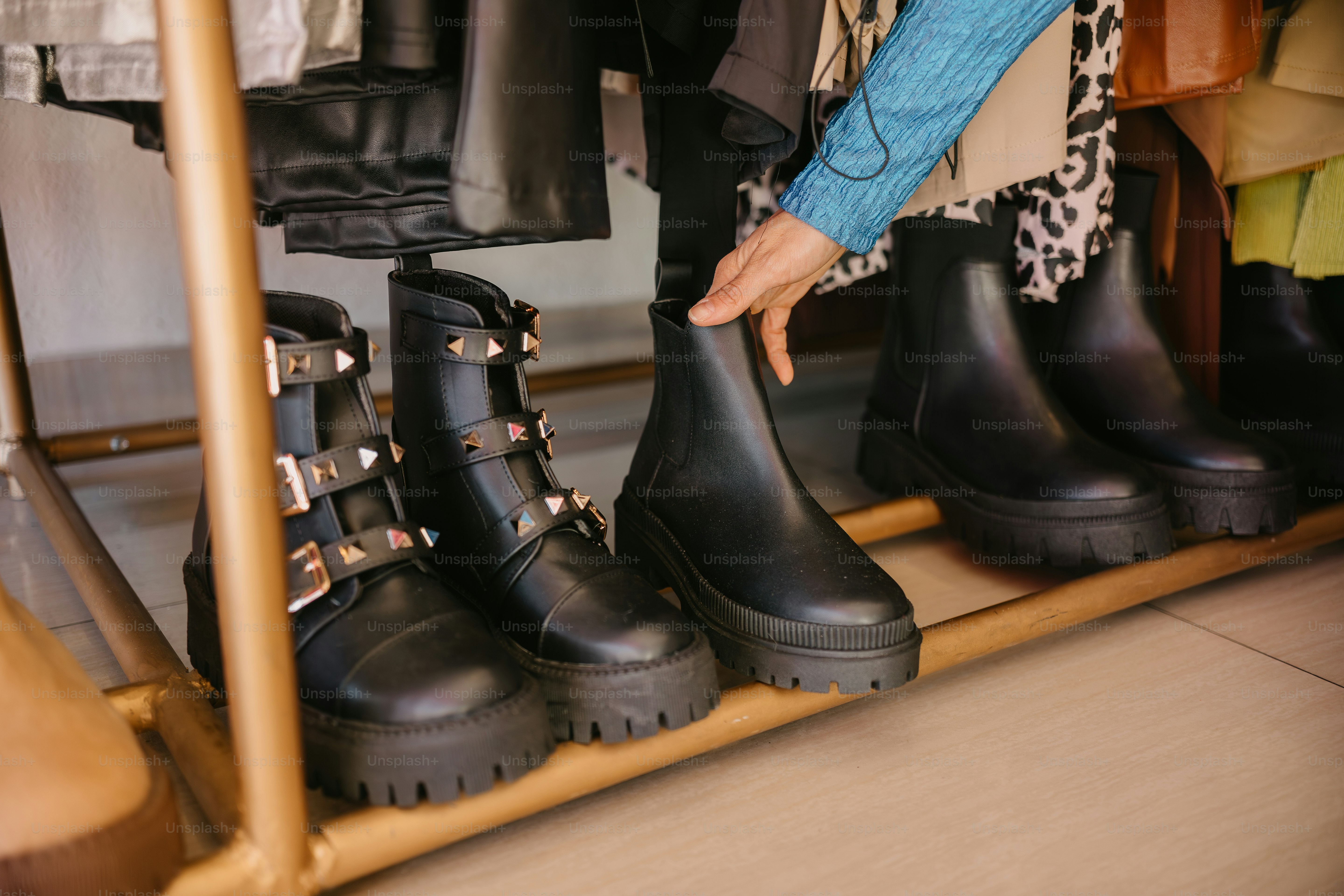 A close up of a person's hand touching a pair of black boots photo ...