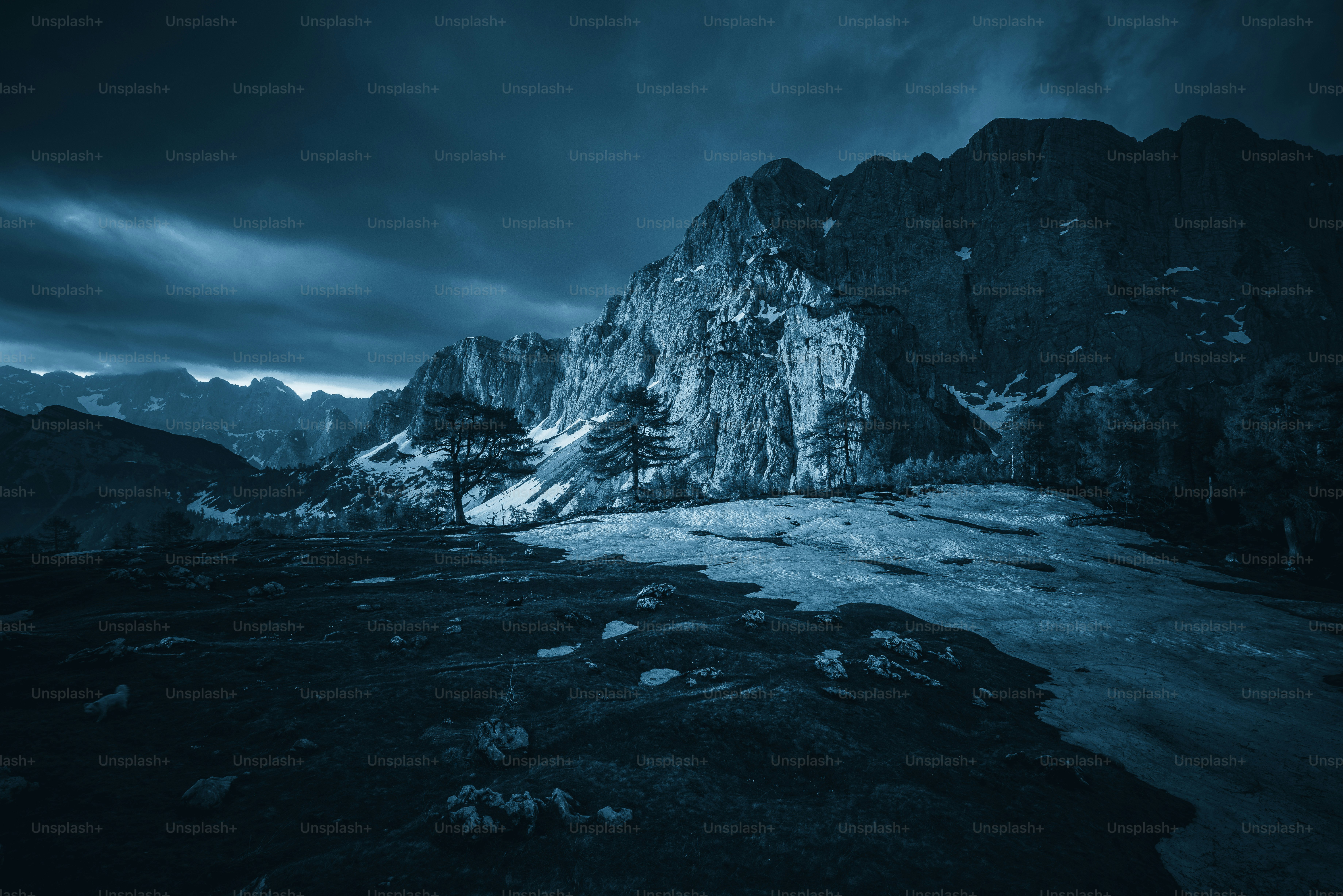A snowy mountain with a dark sky in the background photo – Landscape ...