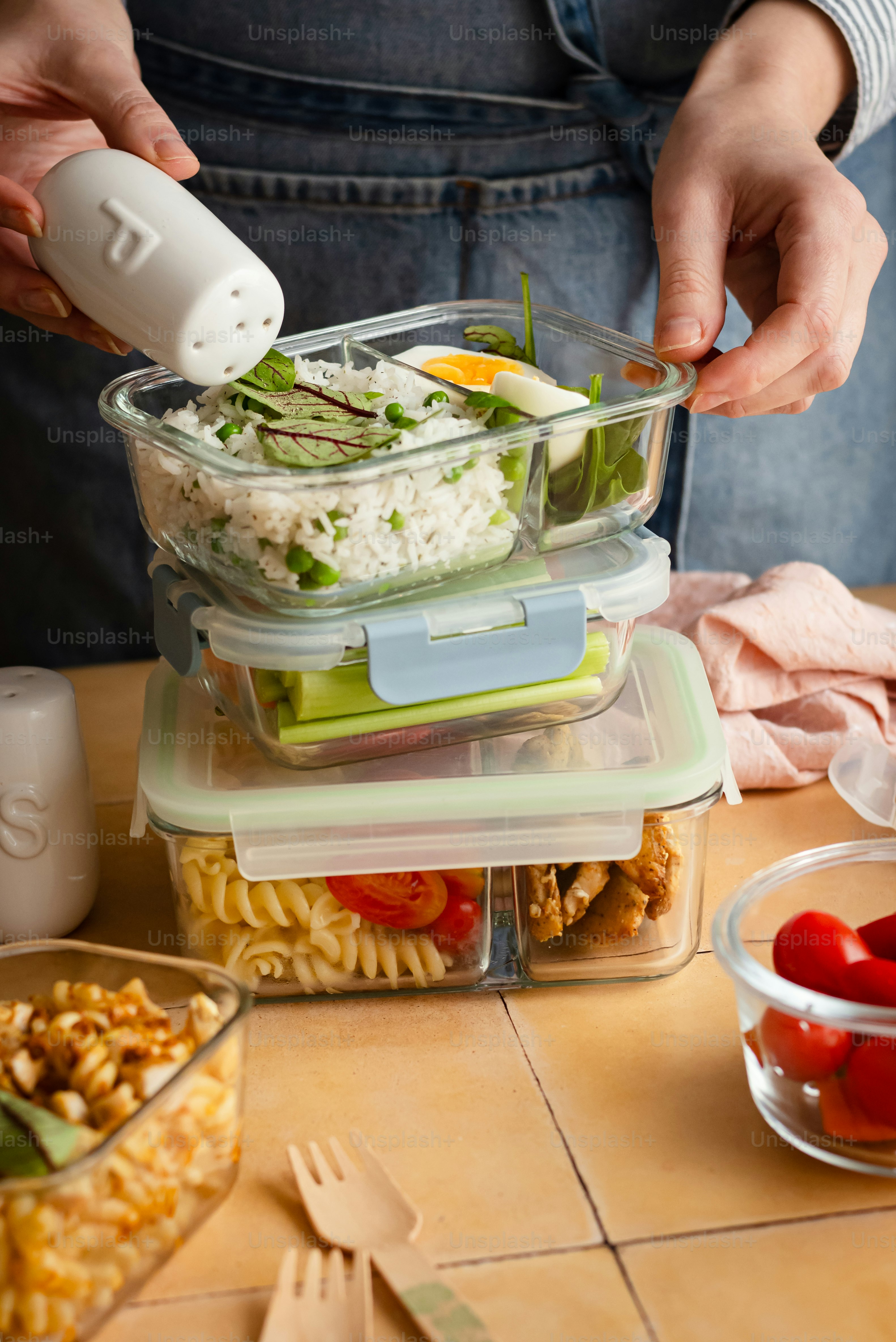 A person putting food in a container on top of a table photo – Meal ...