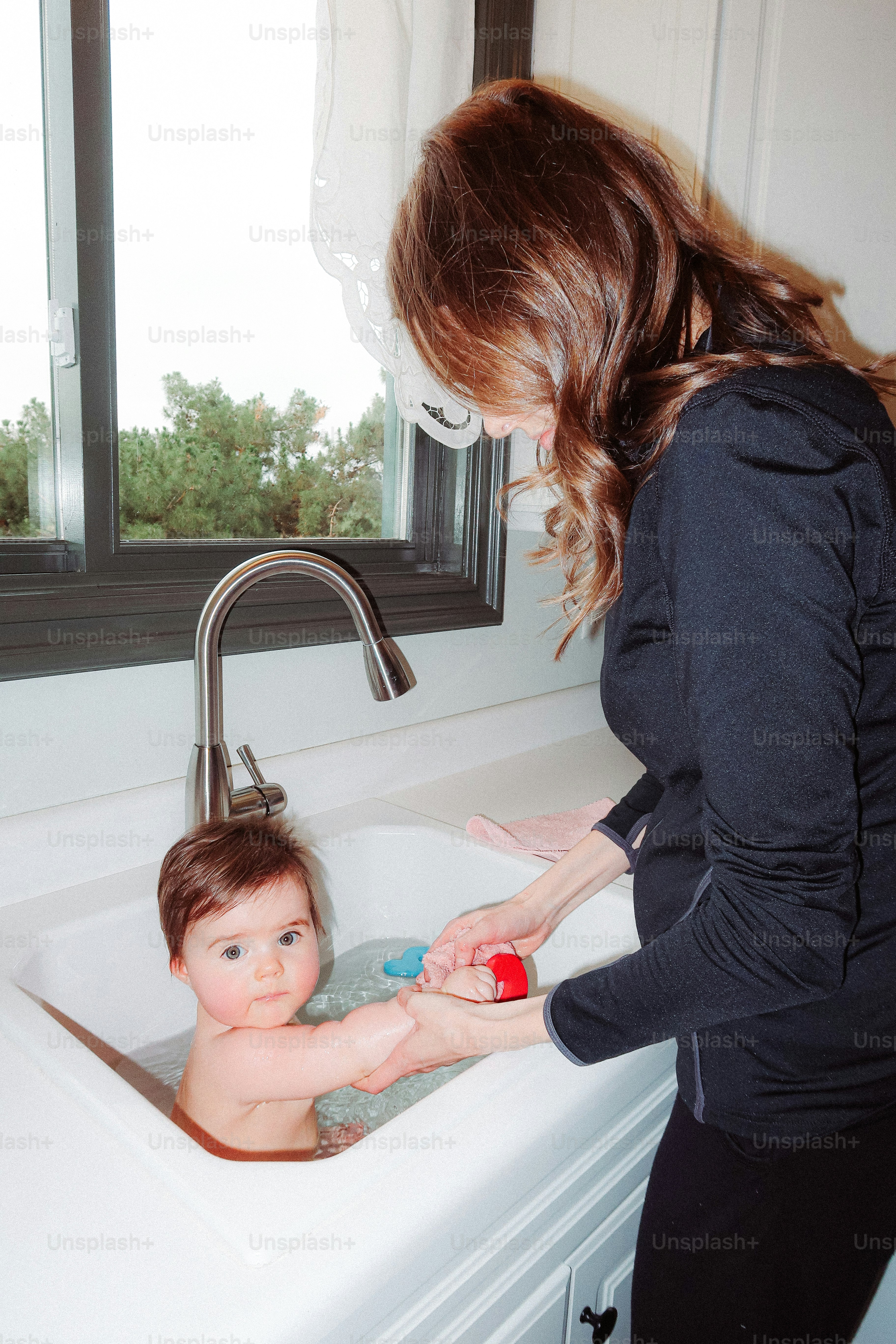 A woman washing a baby in a sink photo – Toddler Image on Unsplash