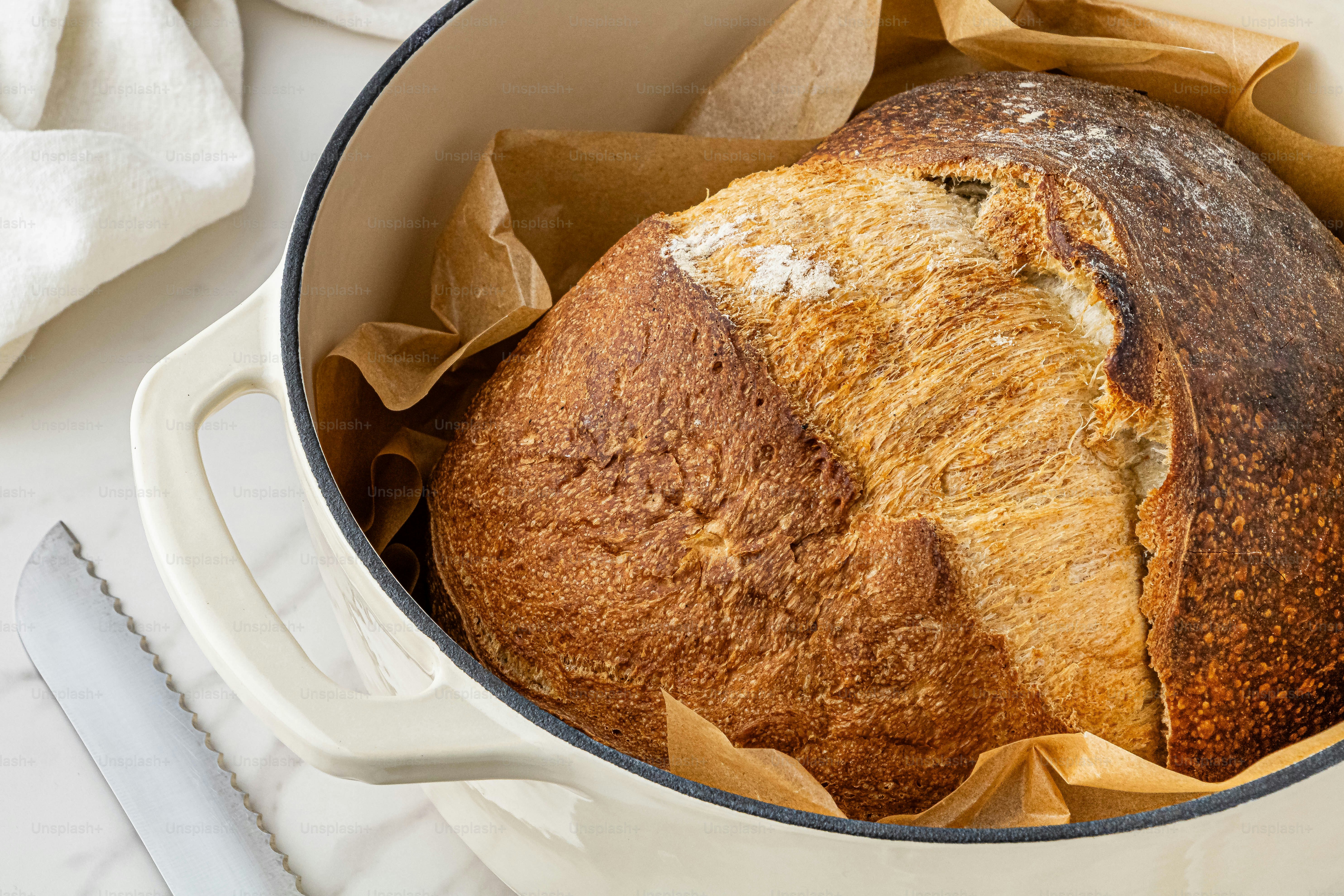 A loaf of bread sitting inside of a white pot photo – Sourdough bread ...