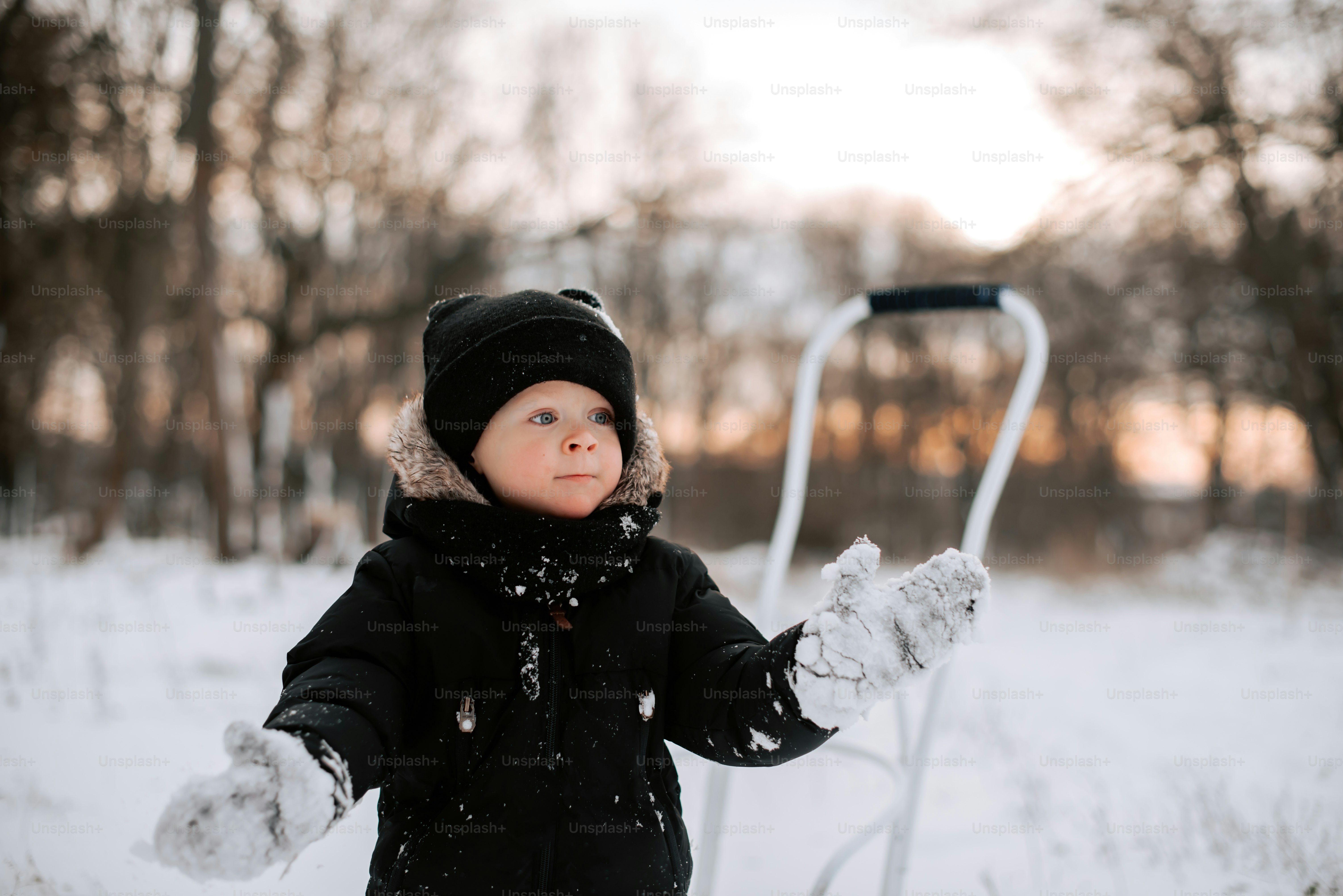 Foto Un niño pequeño jugando en la nieve con un trineo – Jugar en la ...
