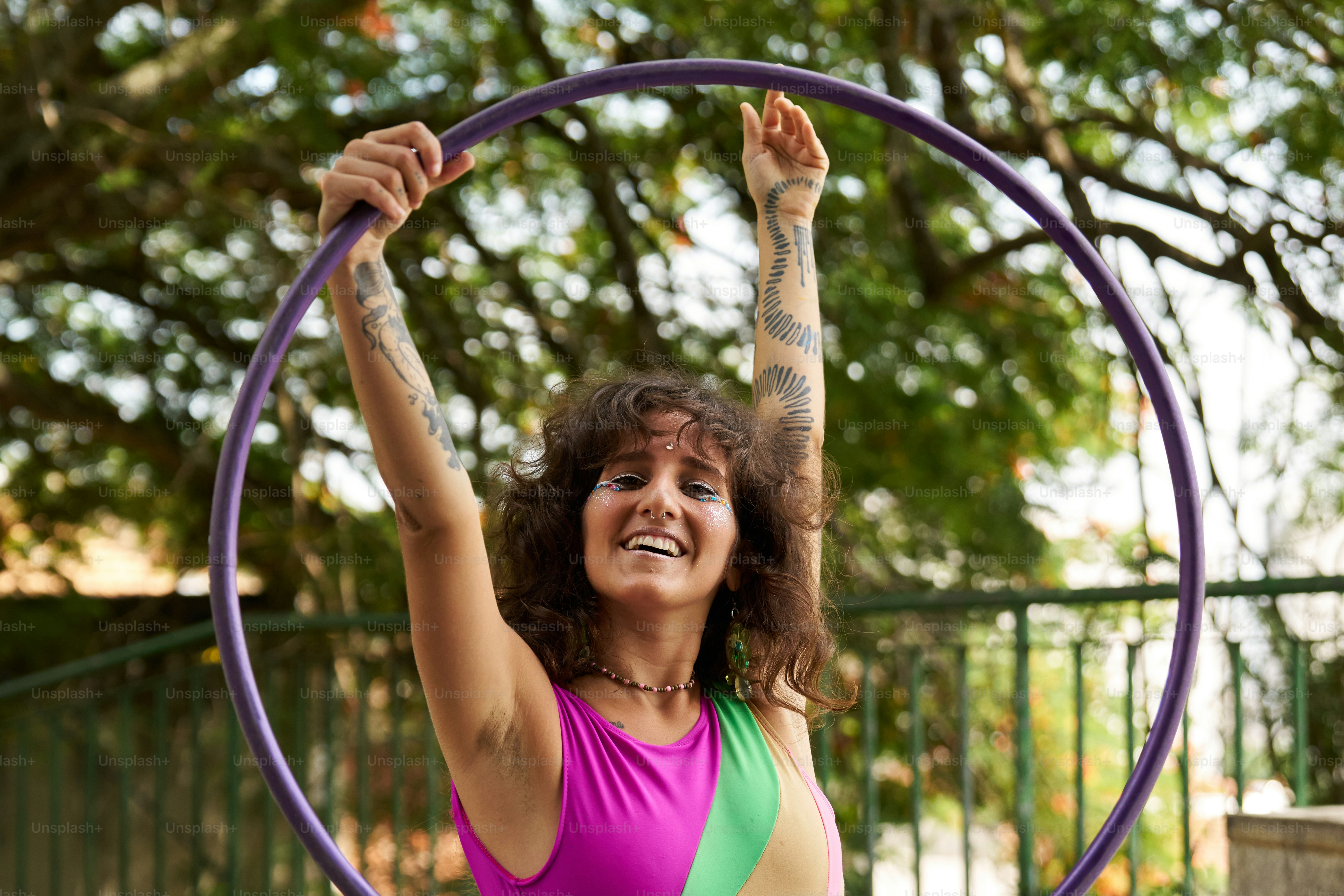 A woman in a purple tank top is holding a purple hula hoop photo ...