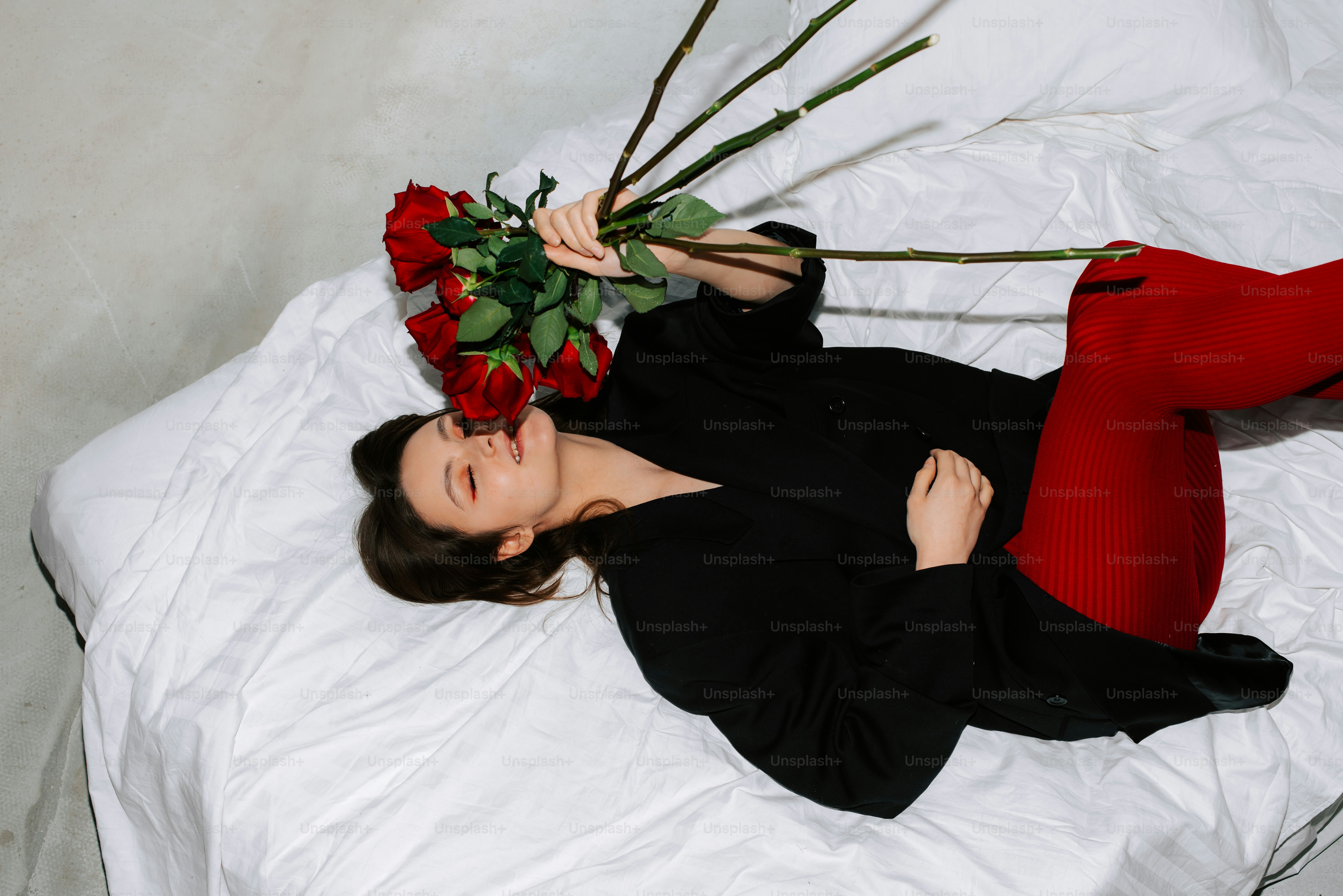 A woman laying on a bed with a bunch of roses on her head photo – Red ...