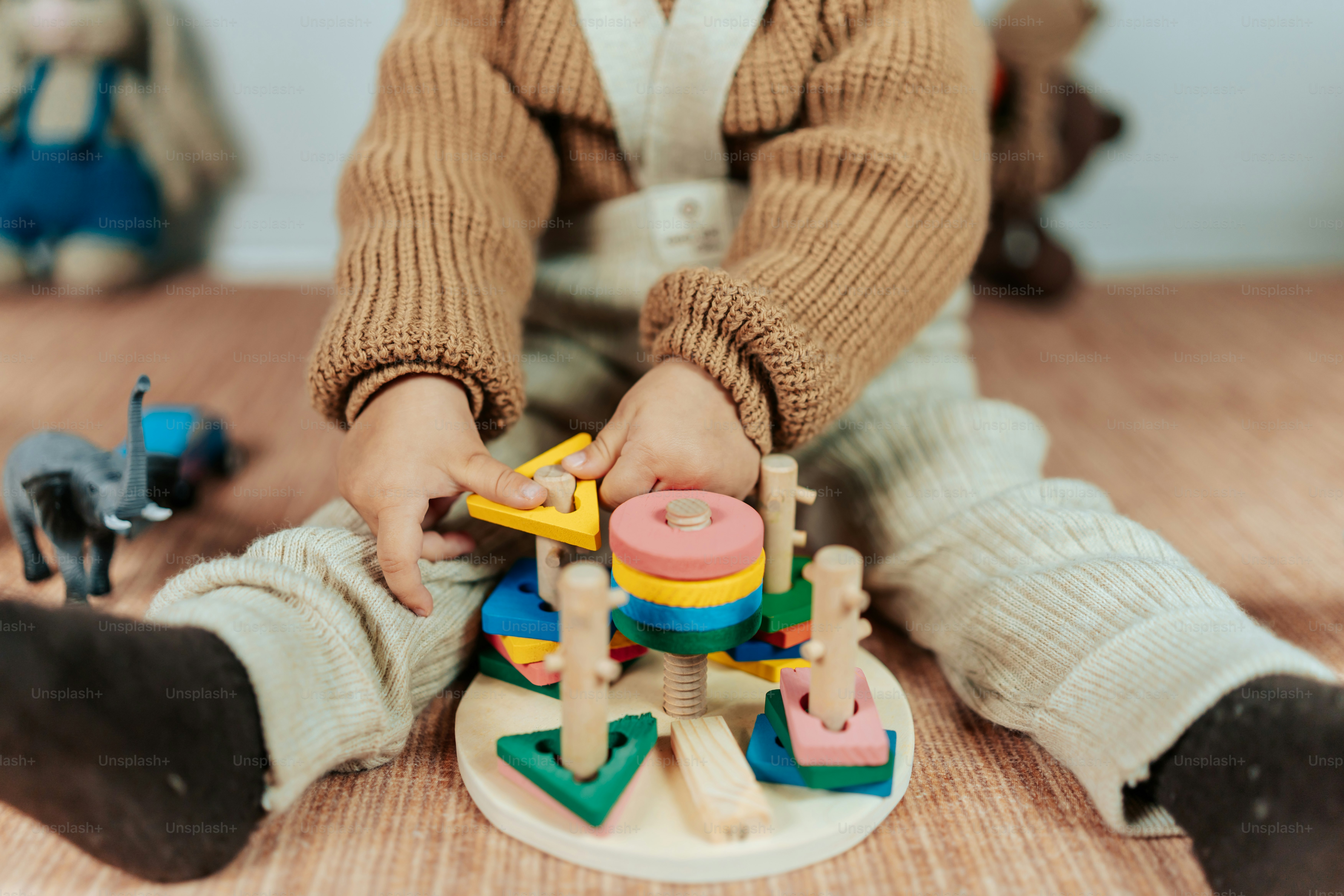A young child playing with toys on the floor photo – Wooden toys Image ...