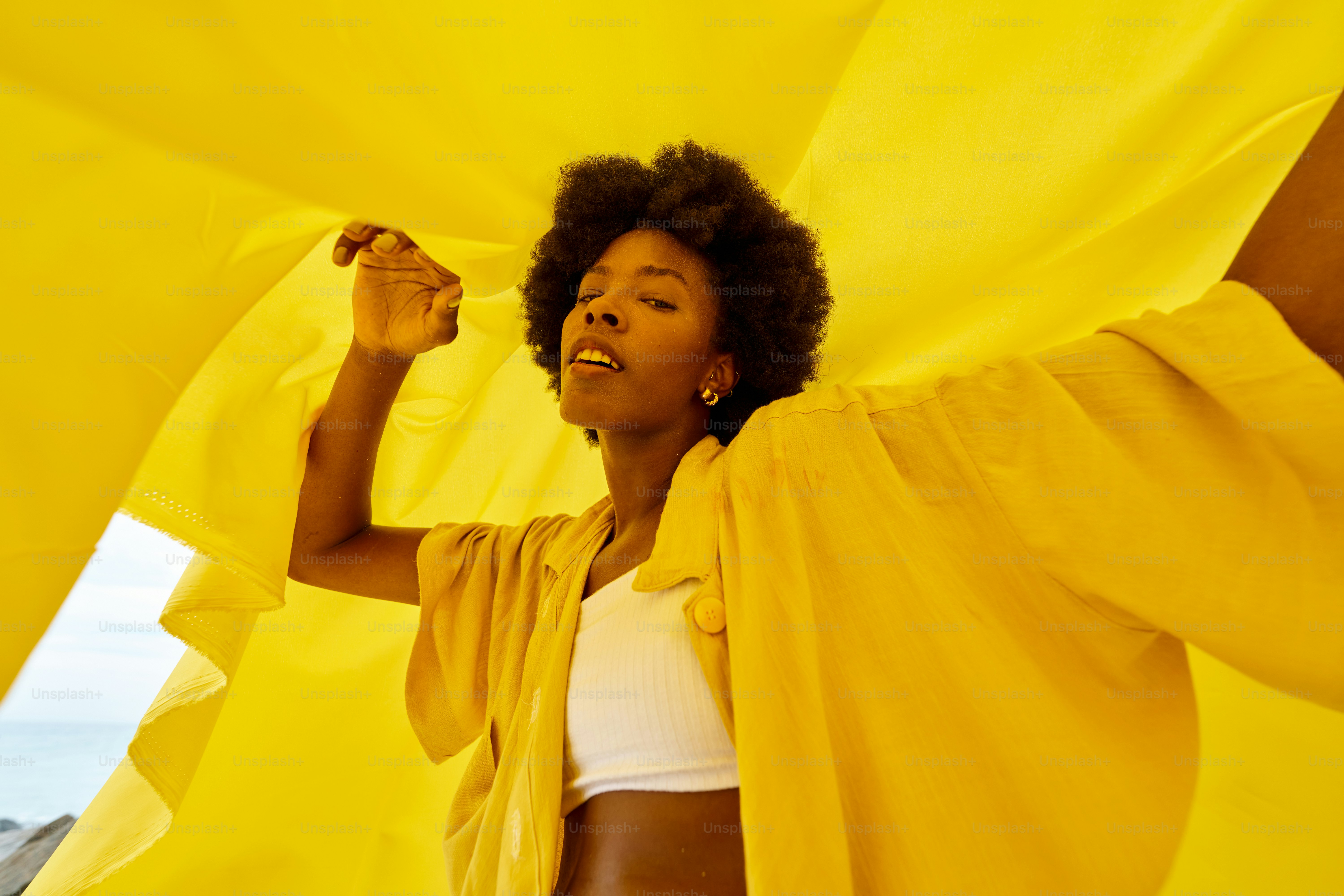 A woman holding a yellow cloth over her head photo – Yellow Image on ...