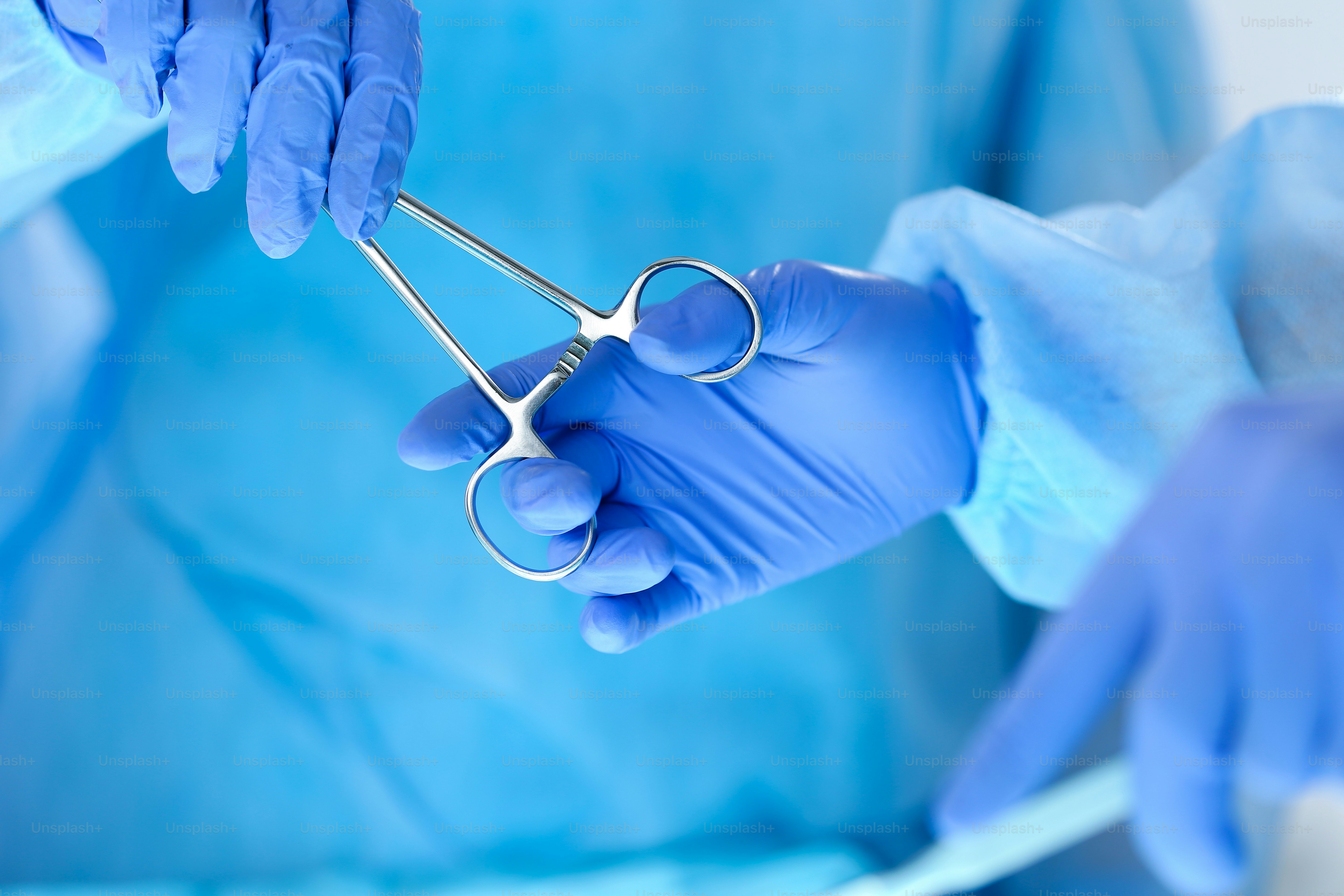 Surgeons hands holding and passing surgical instrument to other doctor ...