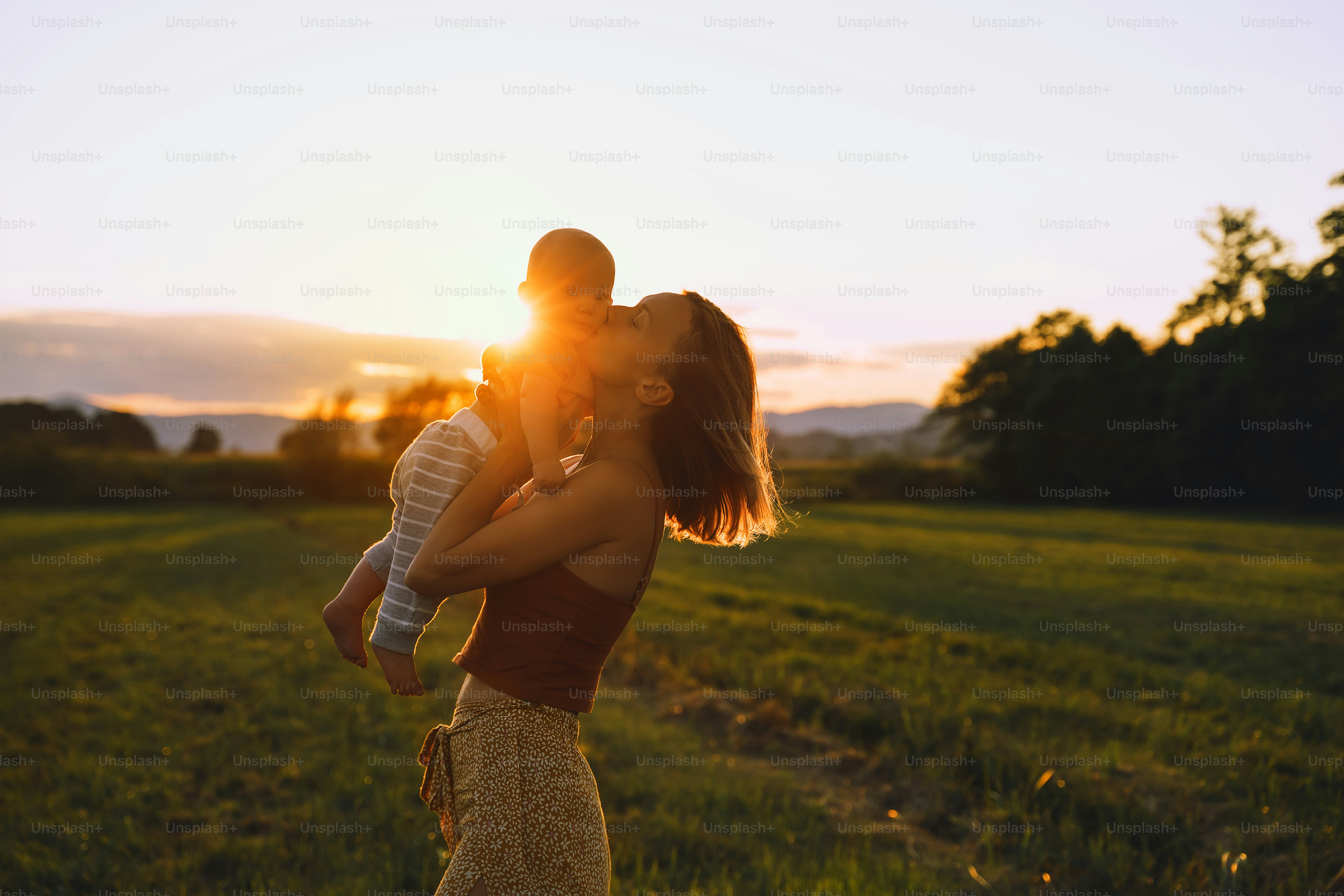Loving mother and baby at sunset. Beautiful woman and small child in ...