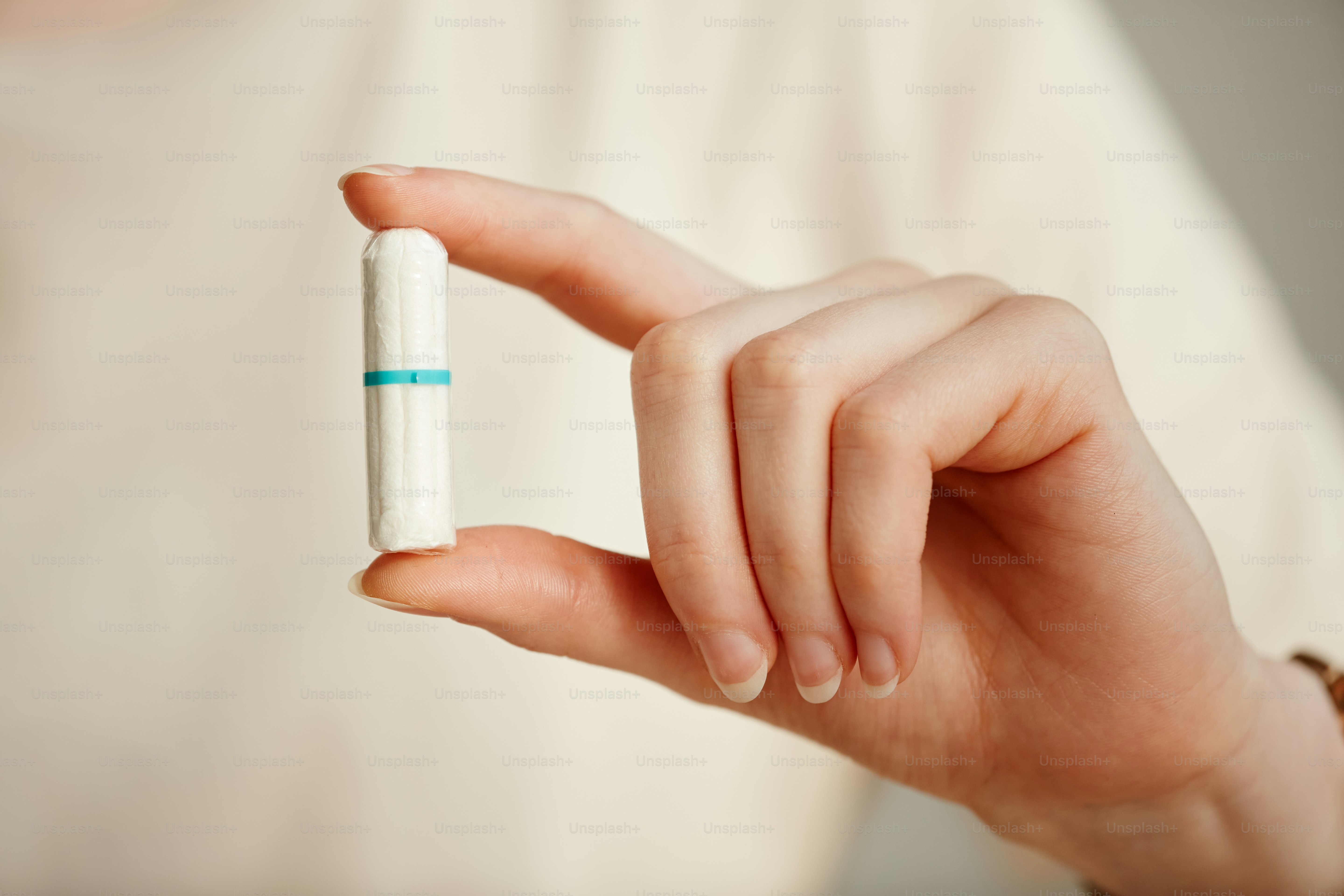 Minimal closeup of young woman holding tampon between two fingers ...
