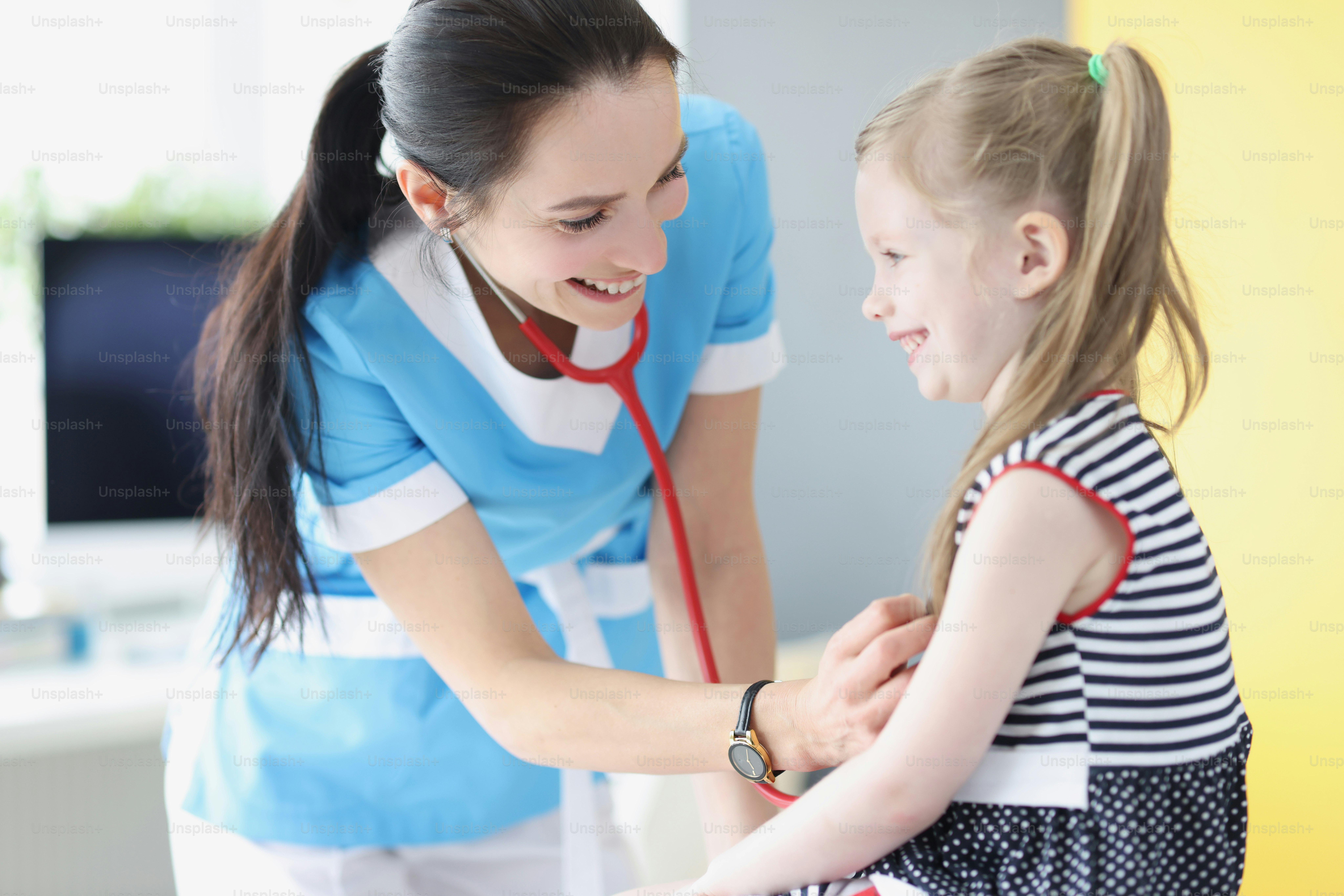 Pediatrician listening to lungs and heart of little girl in clinic ...
