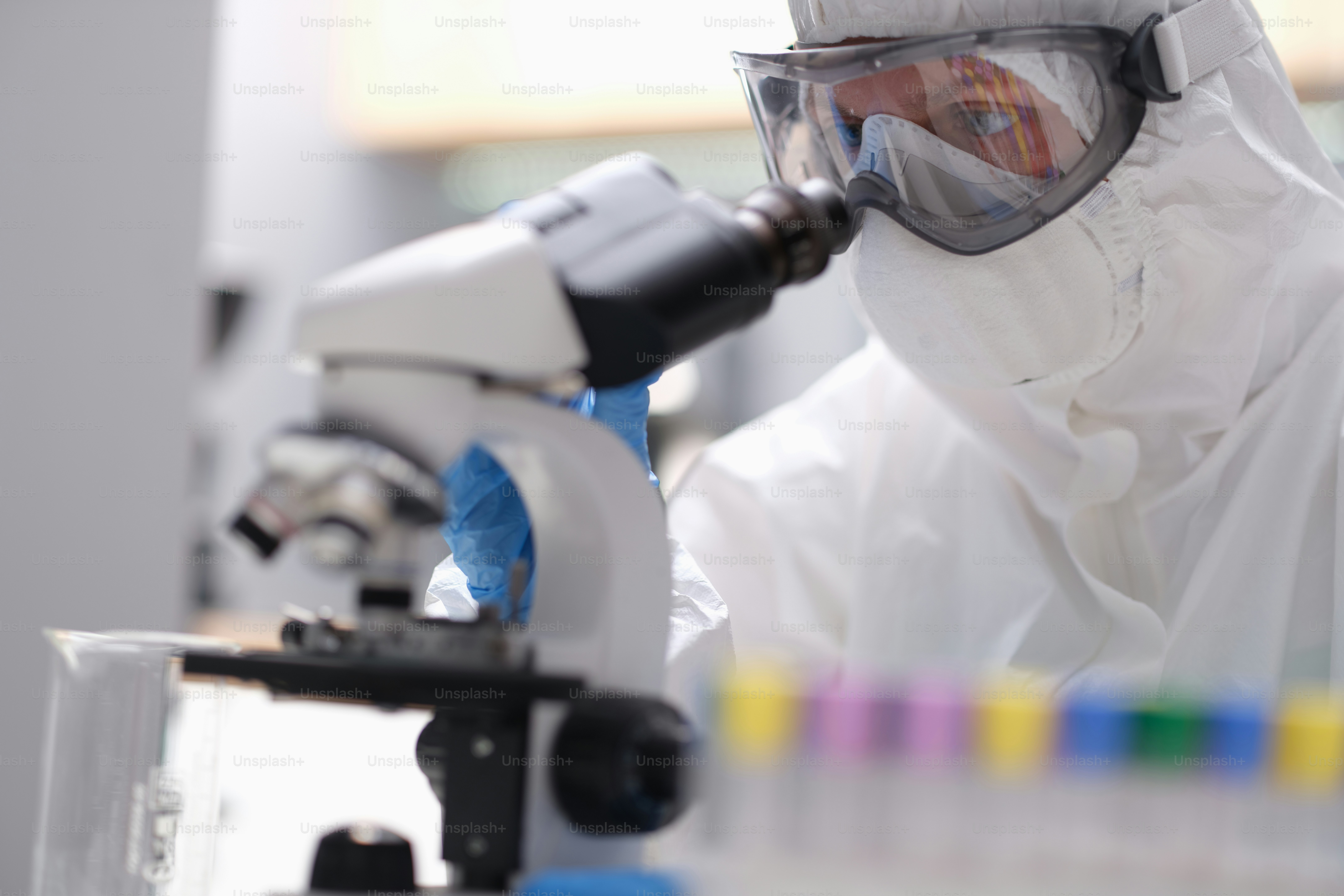 Biologist in protective suit with goggles and medical mask working with ...