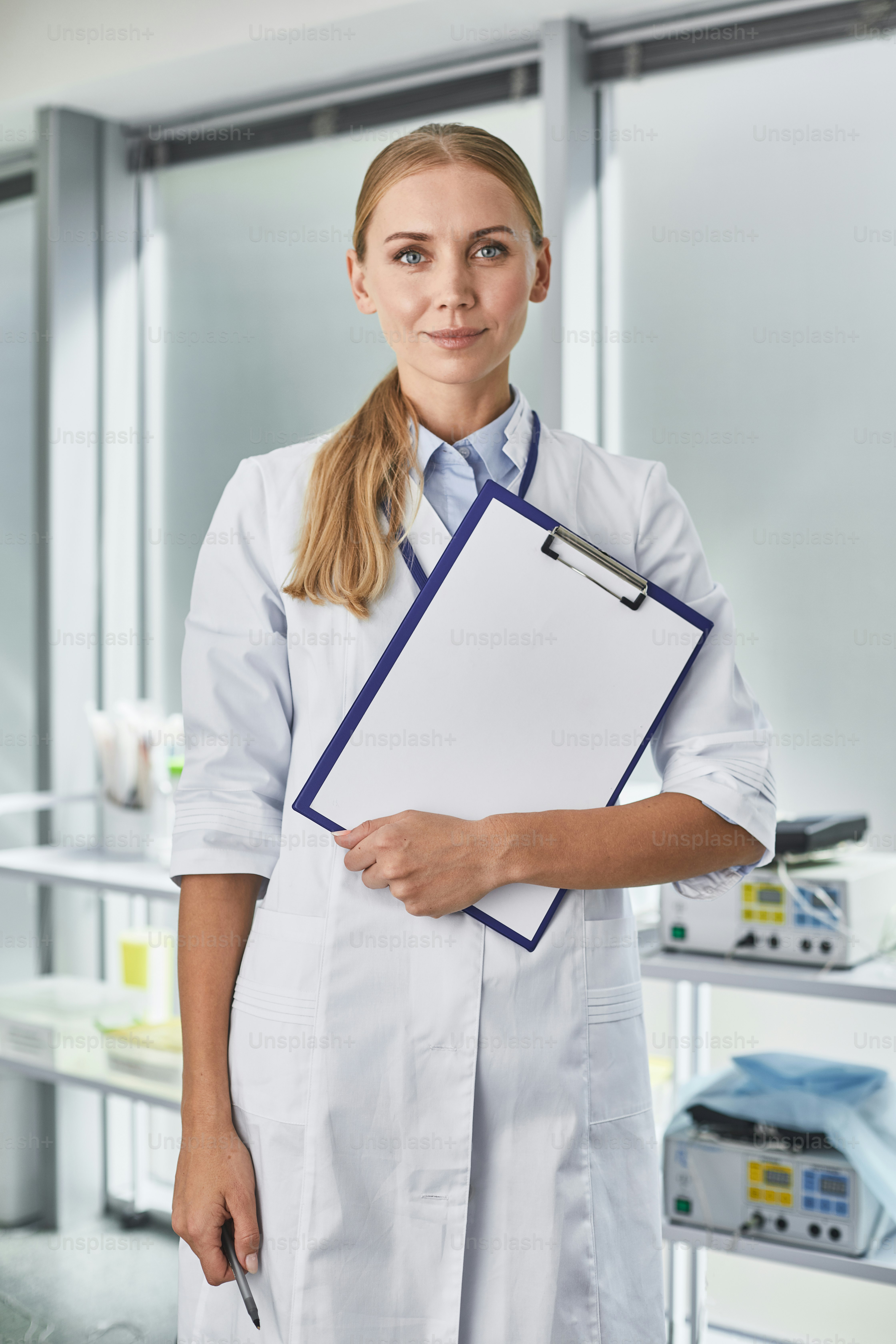 Excellent specialist. Portrait of smiling young woman in white lab coat ...