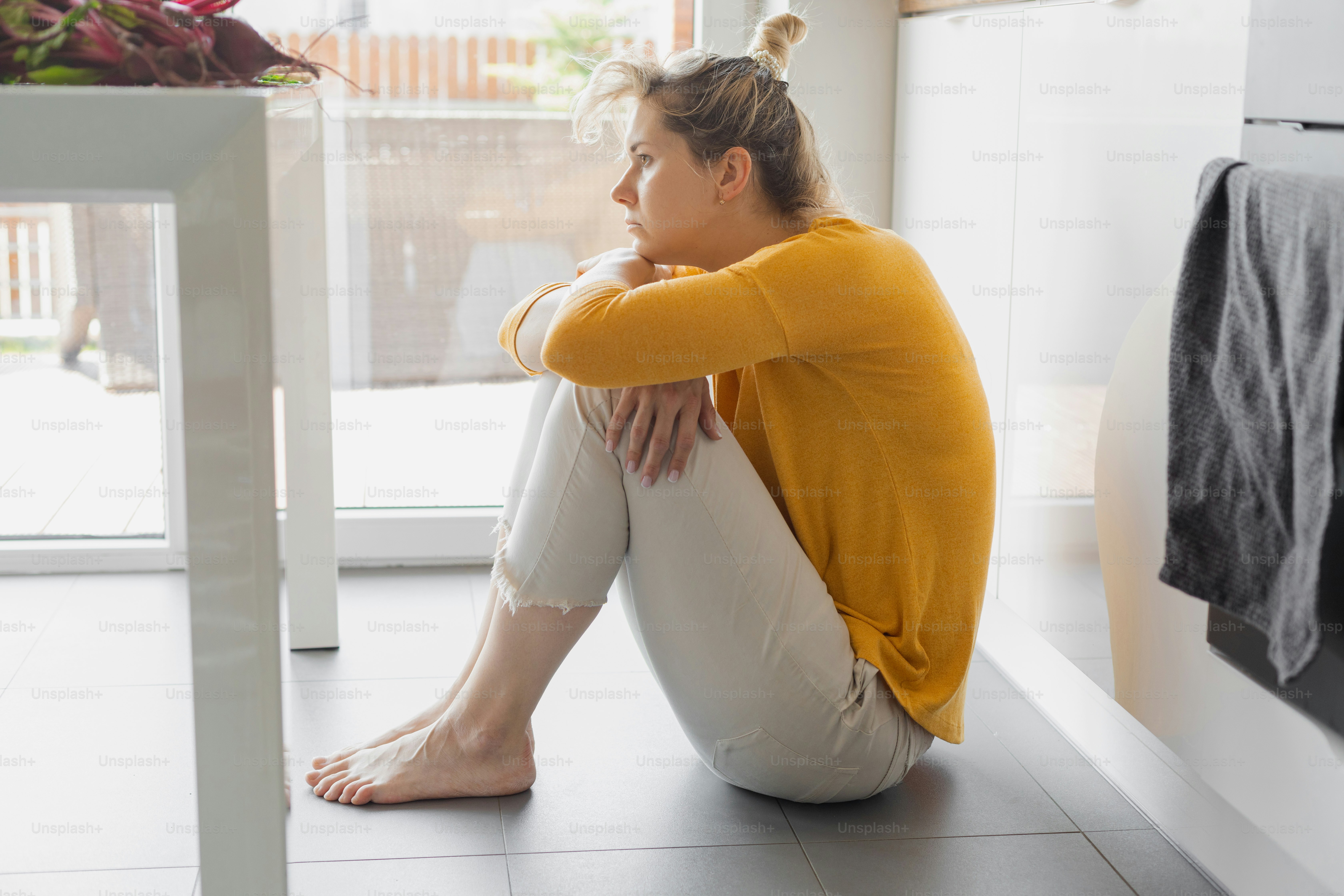 Lonely depressed and sick woman sitting alone on kitchen floor in ...