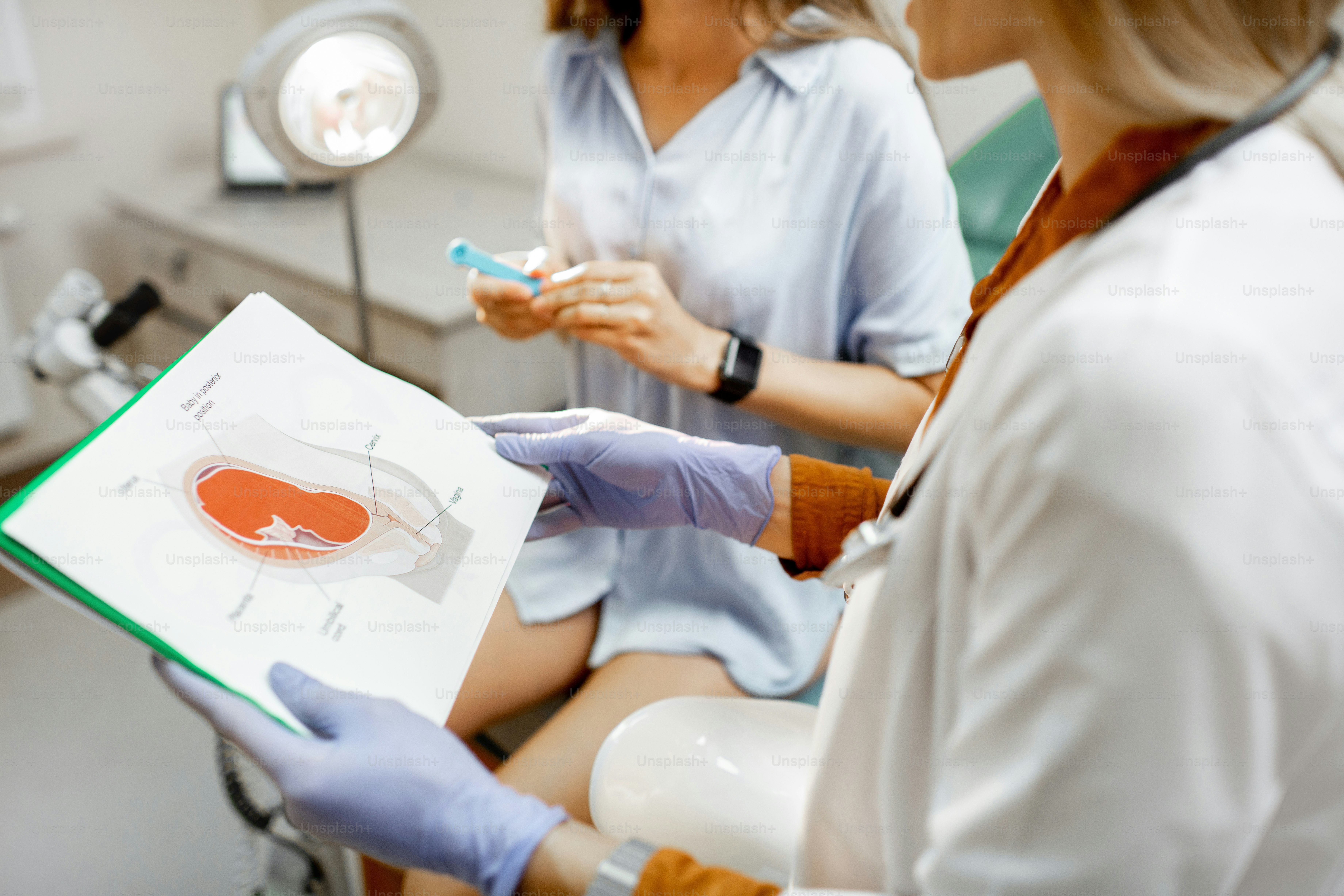 Gynecologist showing a picture with uterus to a young woman patient ...