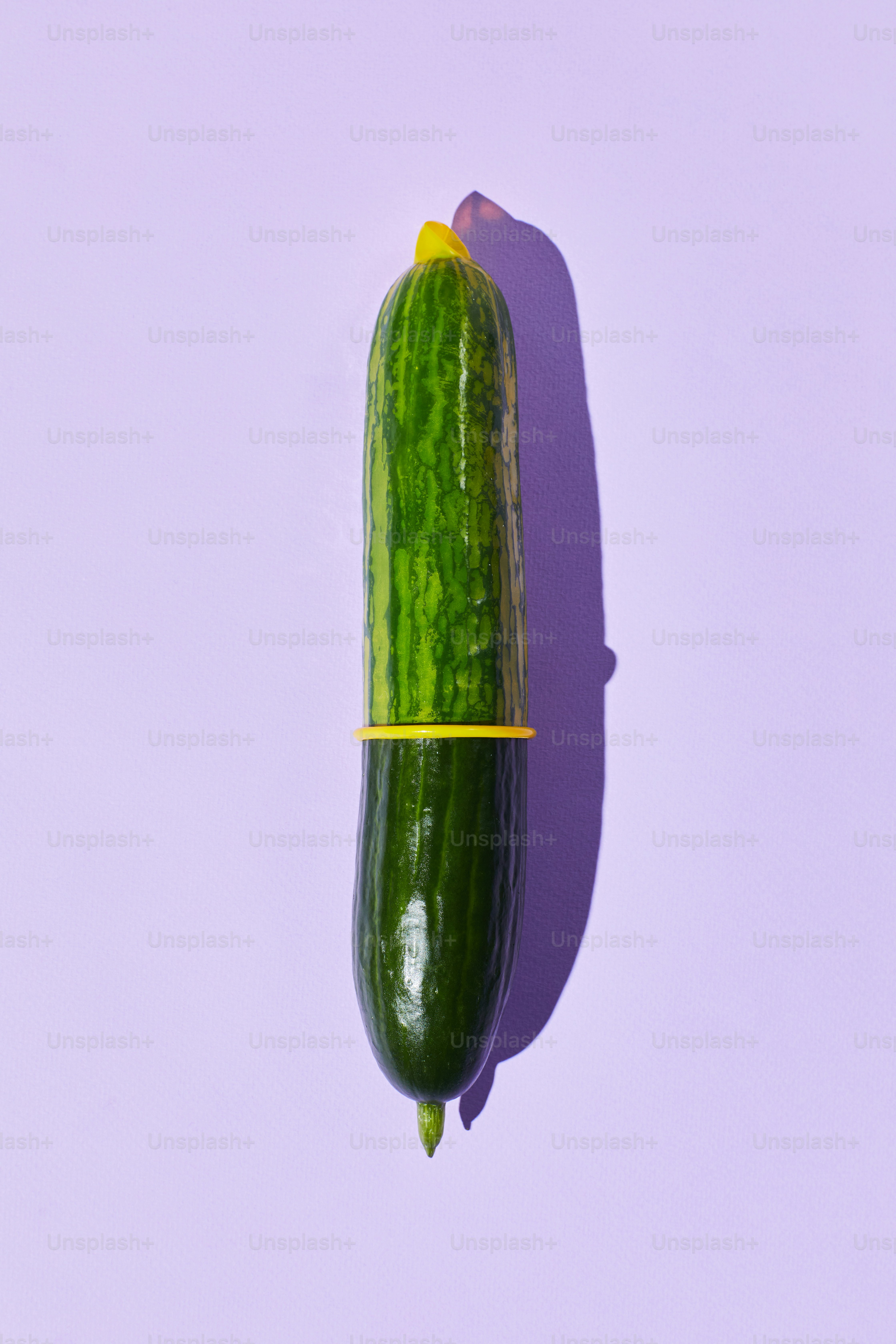 Close up of single cucumber with condom safe sex and protection concept ...
