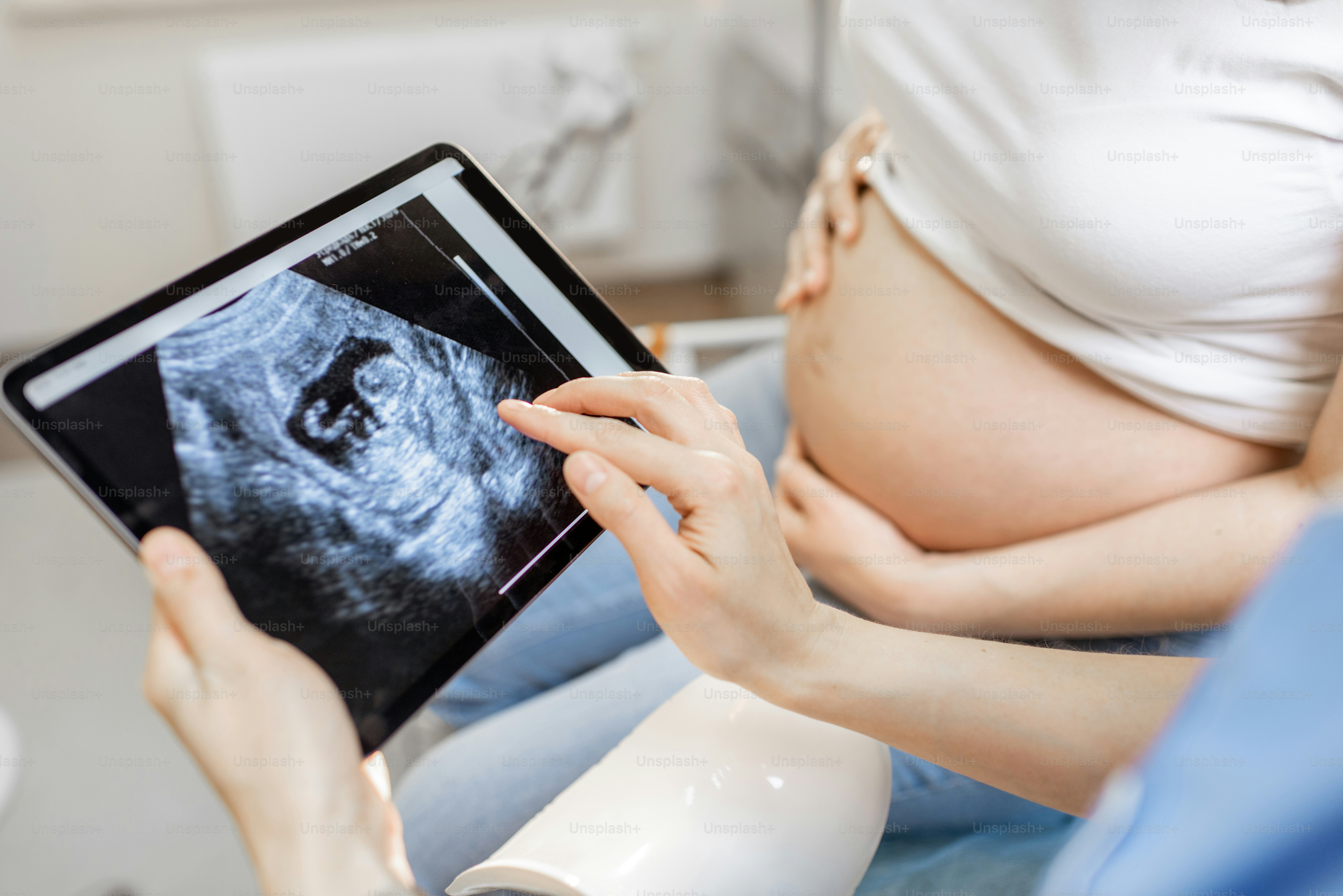 Doctor with an ultrasound scan of unborn child on a digital tablet ...