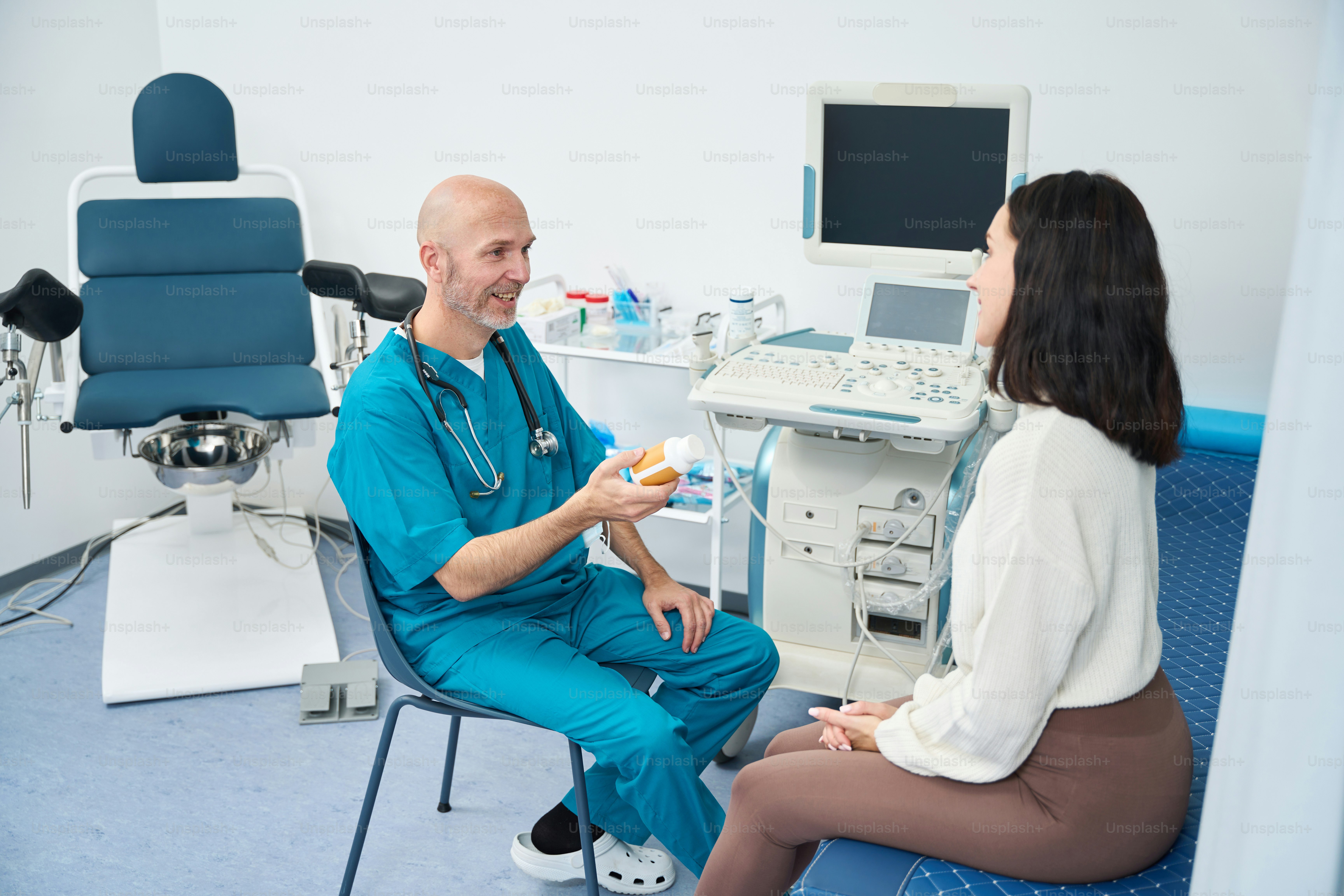 Joyful gynecologist sits in front of a woman while she listens about ...