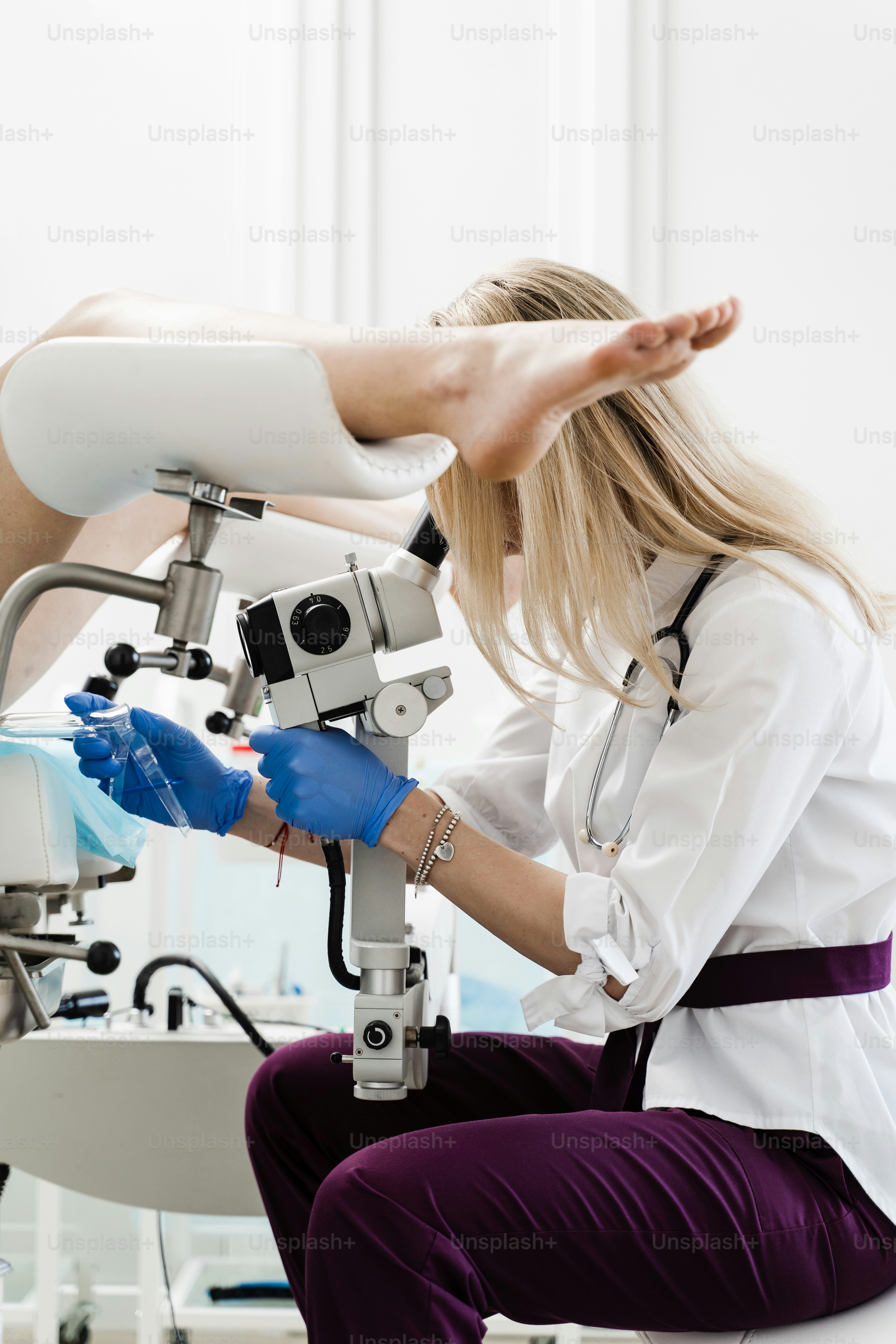 Gynecologist is looking in colposcope for detail examination of disease ...