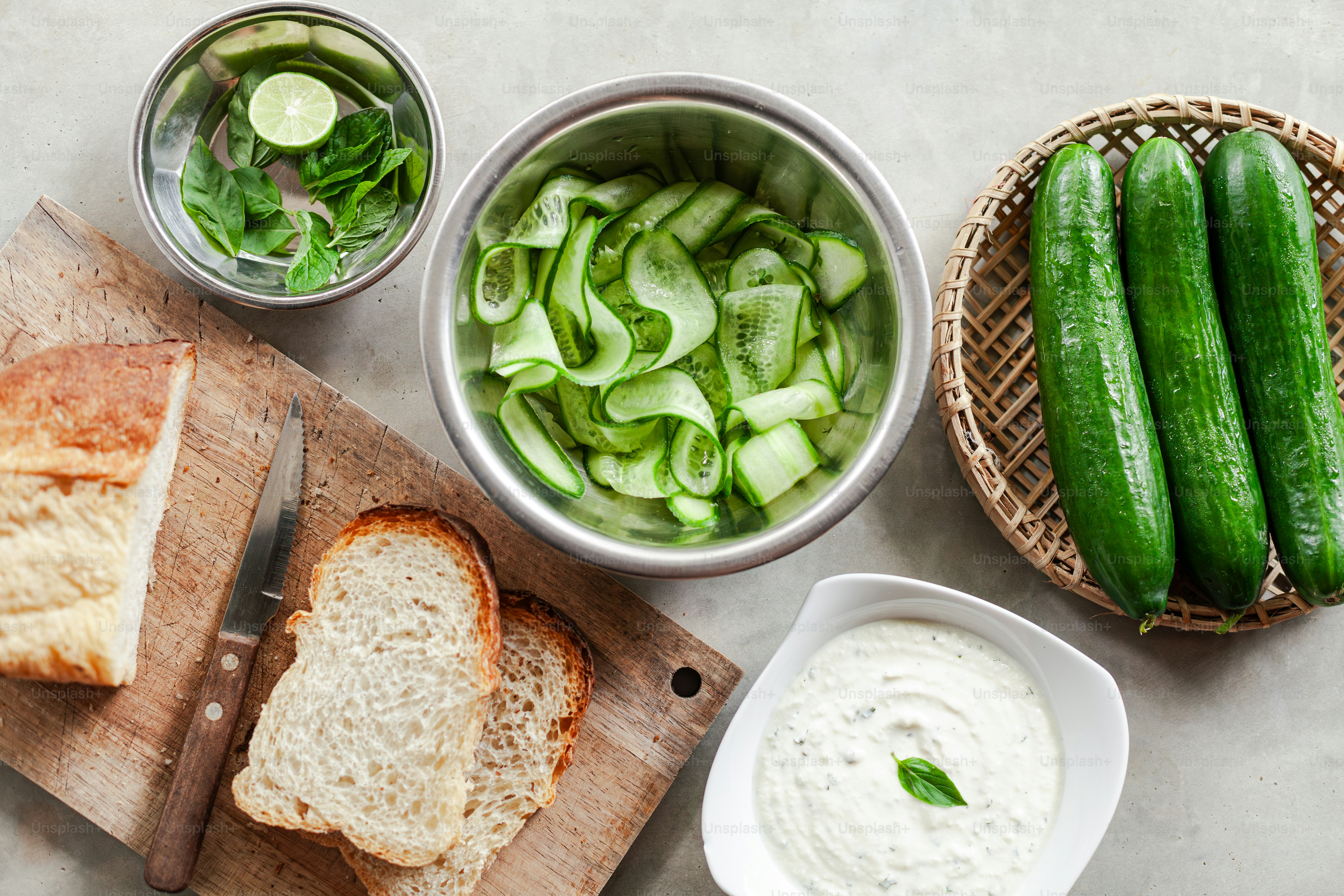 A cutting board topped with sliced cucumbers next to a bowl of pickles ...